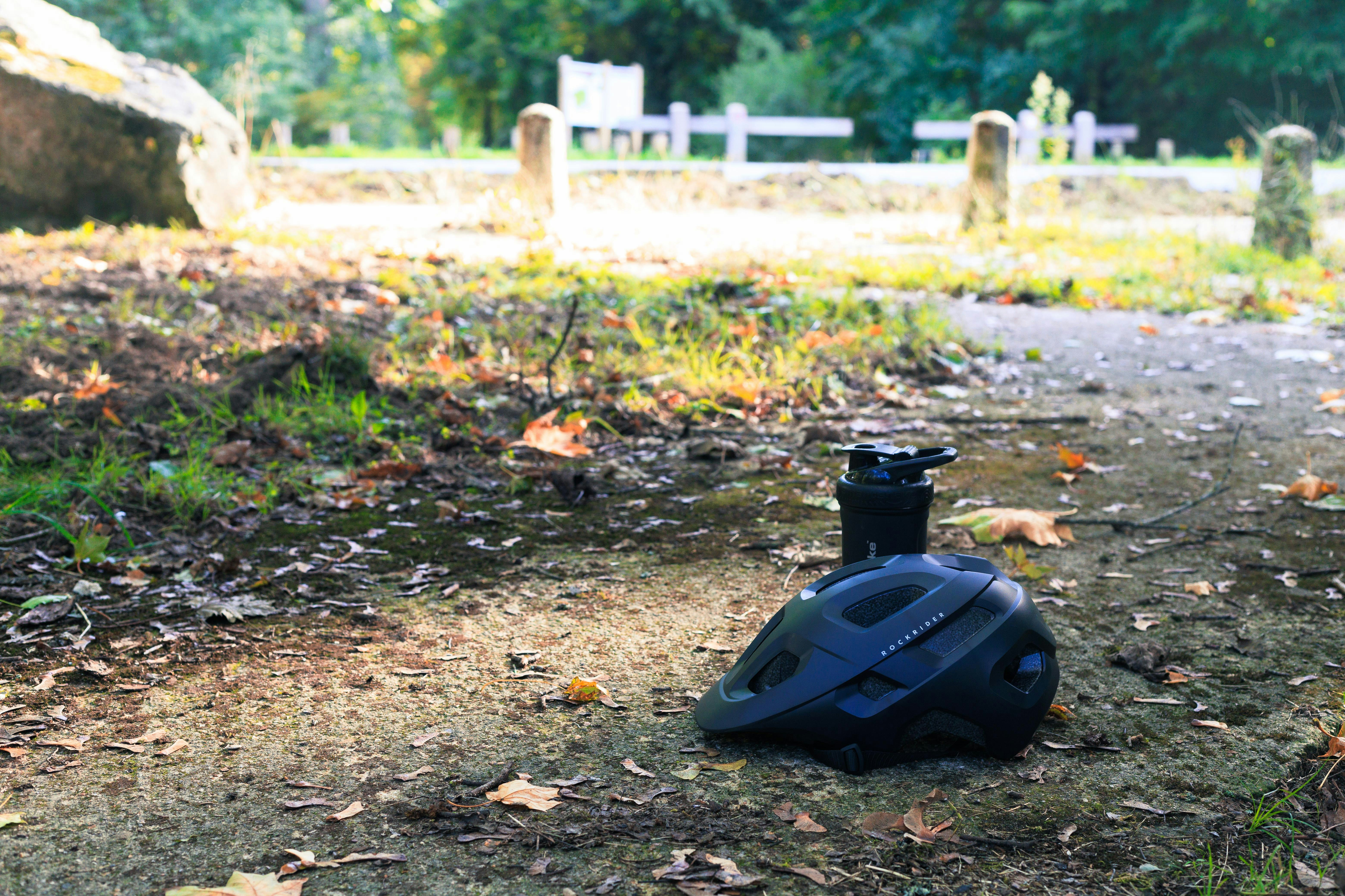 Grounded Focus: A lone helmet with a camera mount rests on a sunlit park dirt path.