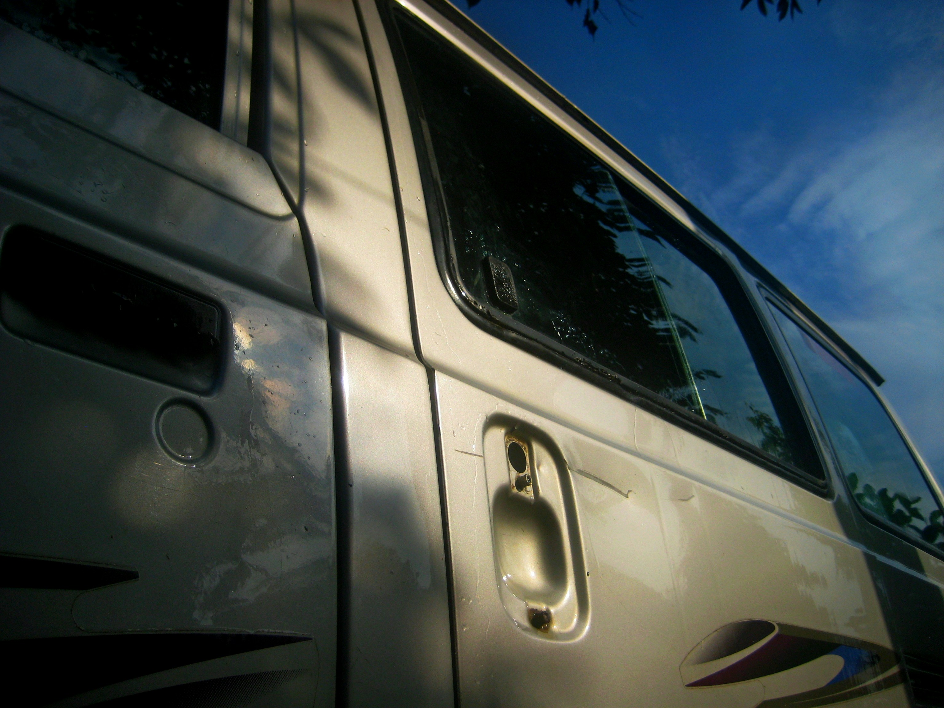 Maruti Omni (Car) | Silver van door against a blue sky.