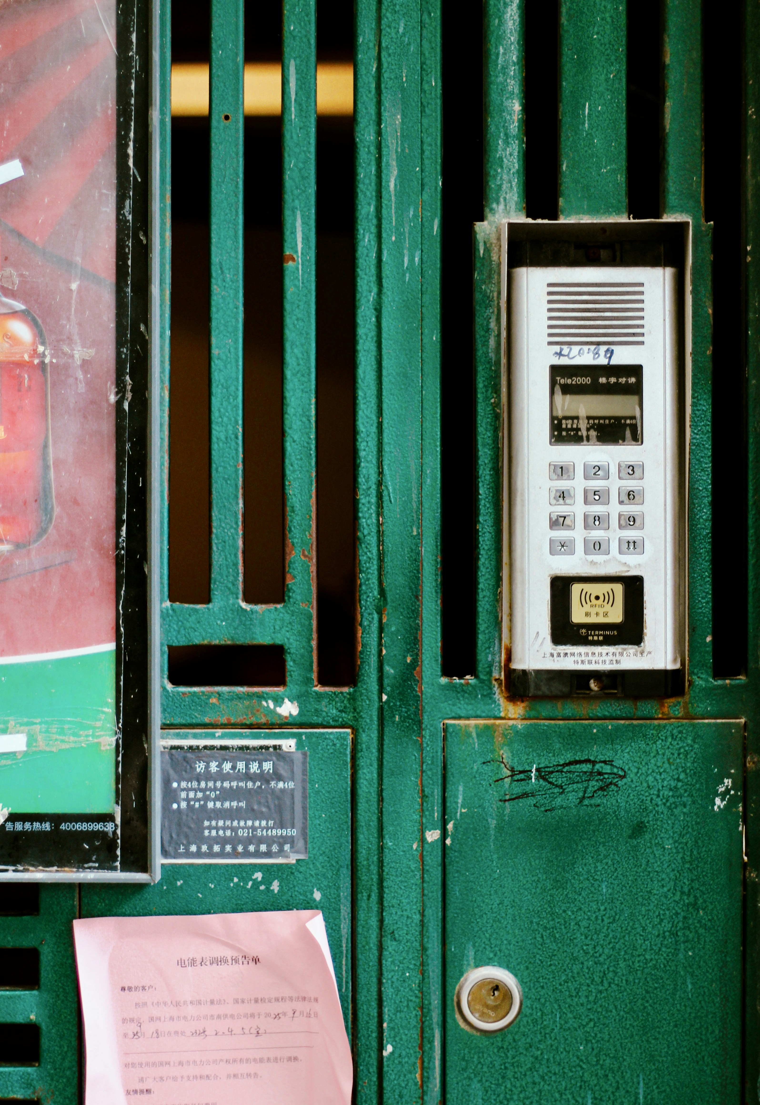 Green metal gate with intercom and notice