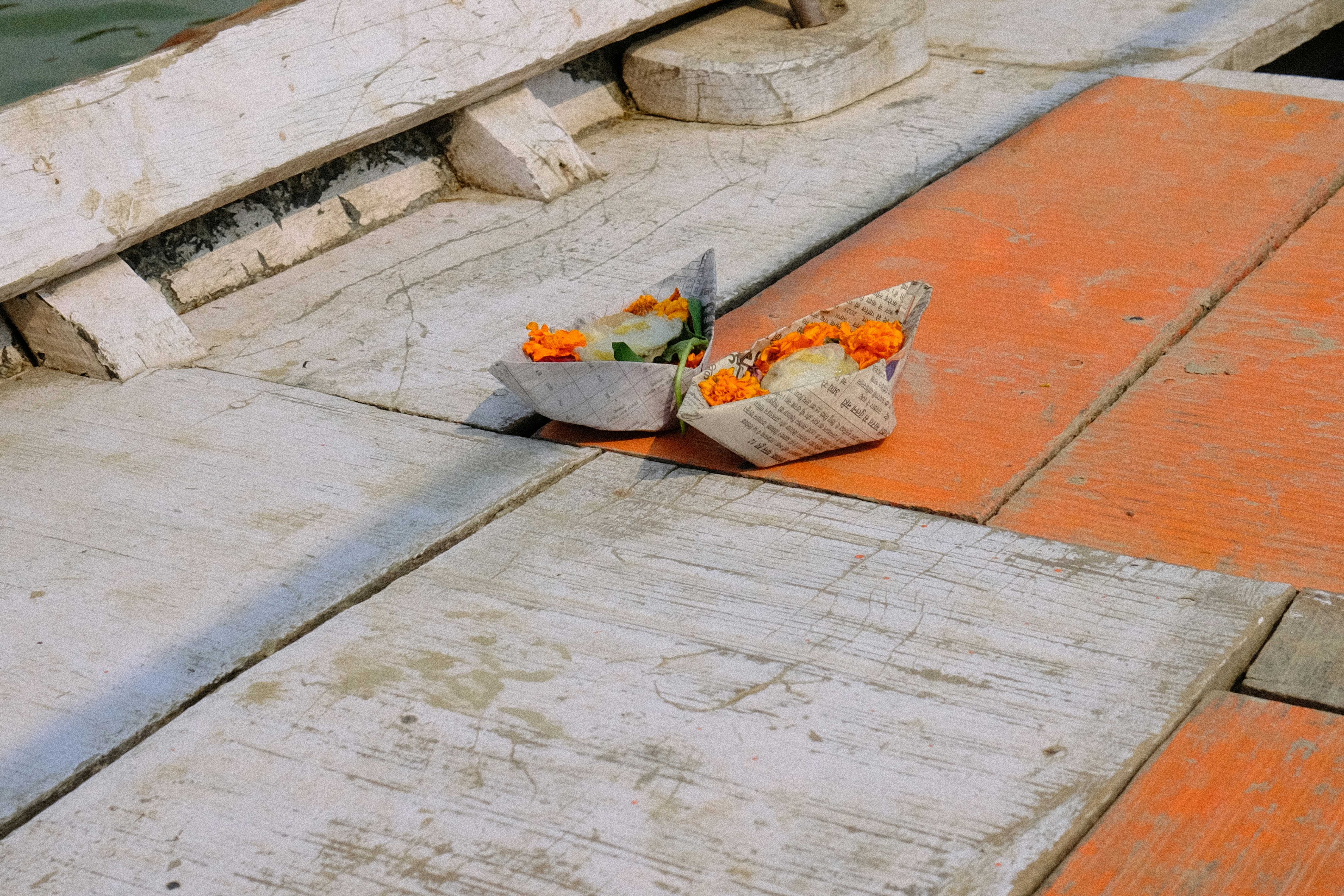 Two Paper Boats with Marigolds Rest on a Weathered Wharf