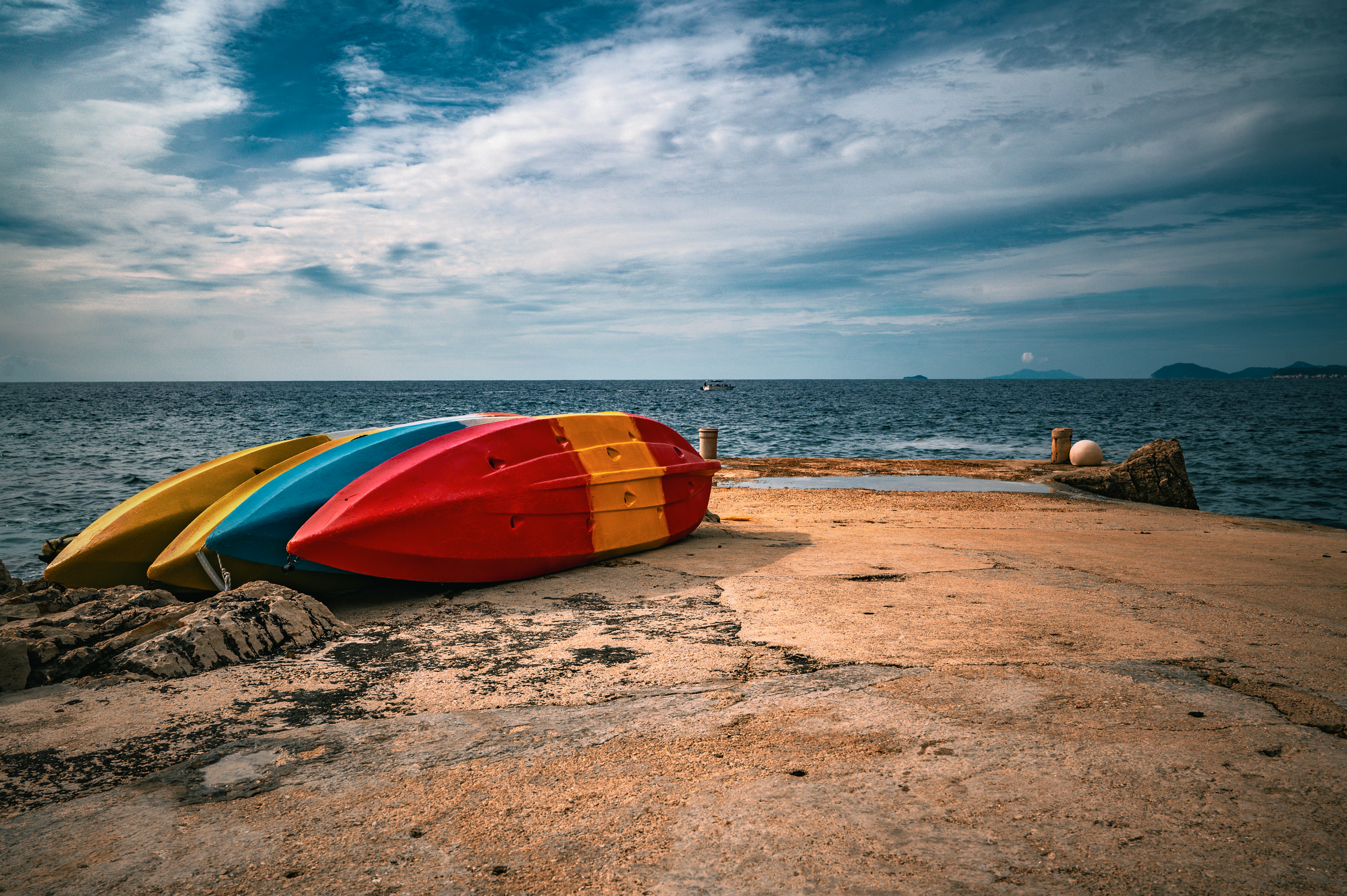 Vivid Kayaks on a Weathered Pier at the Edge of a Quiet Sea