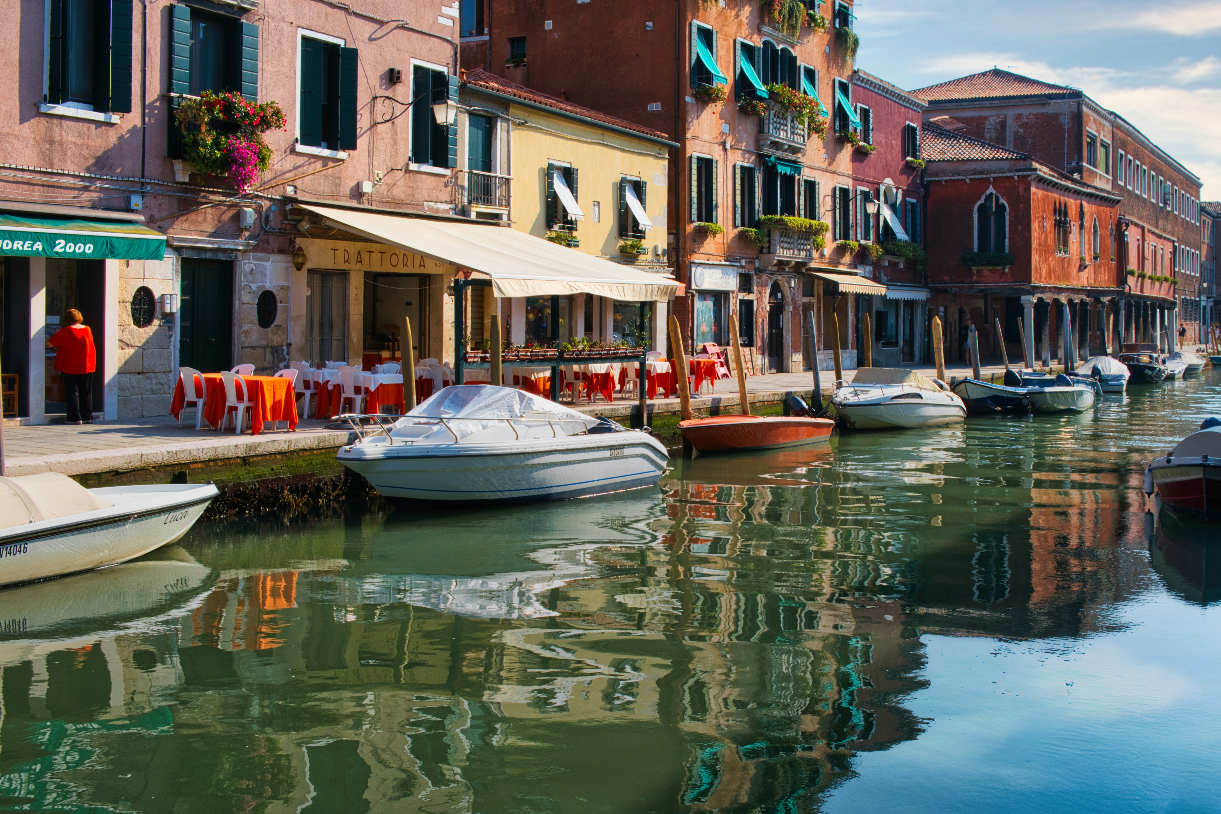 Boats docked along a canal beside colorful buildings.