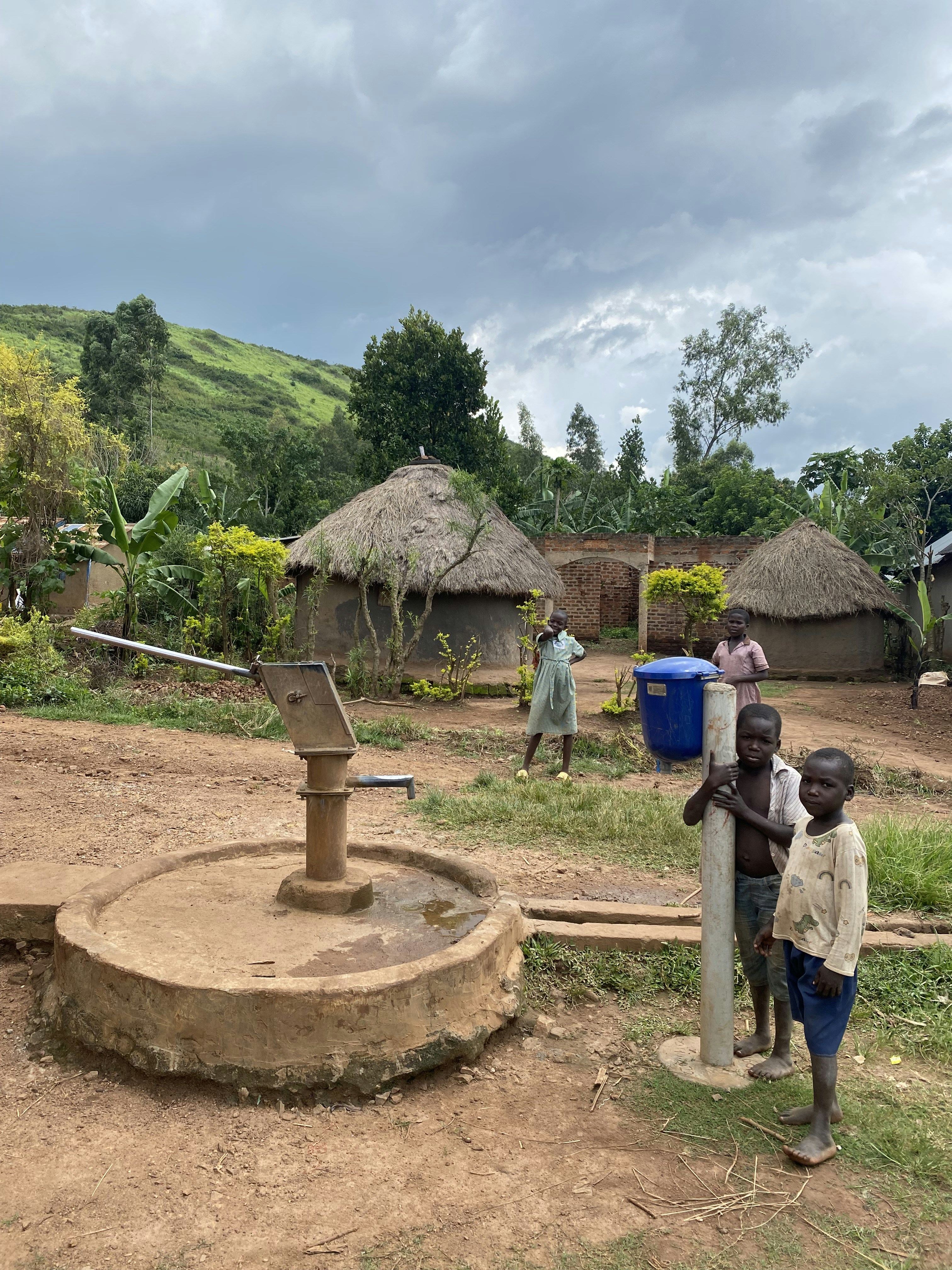 Children standing near a Borehole | Children stand by a water pump in a village.