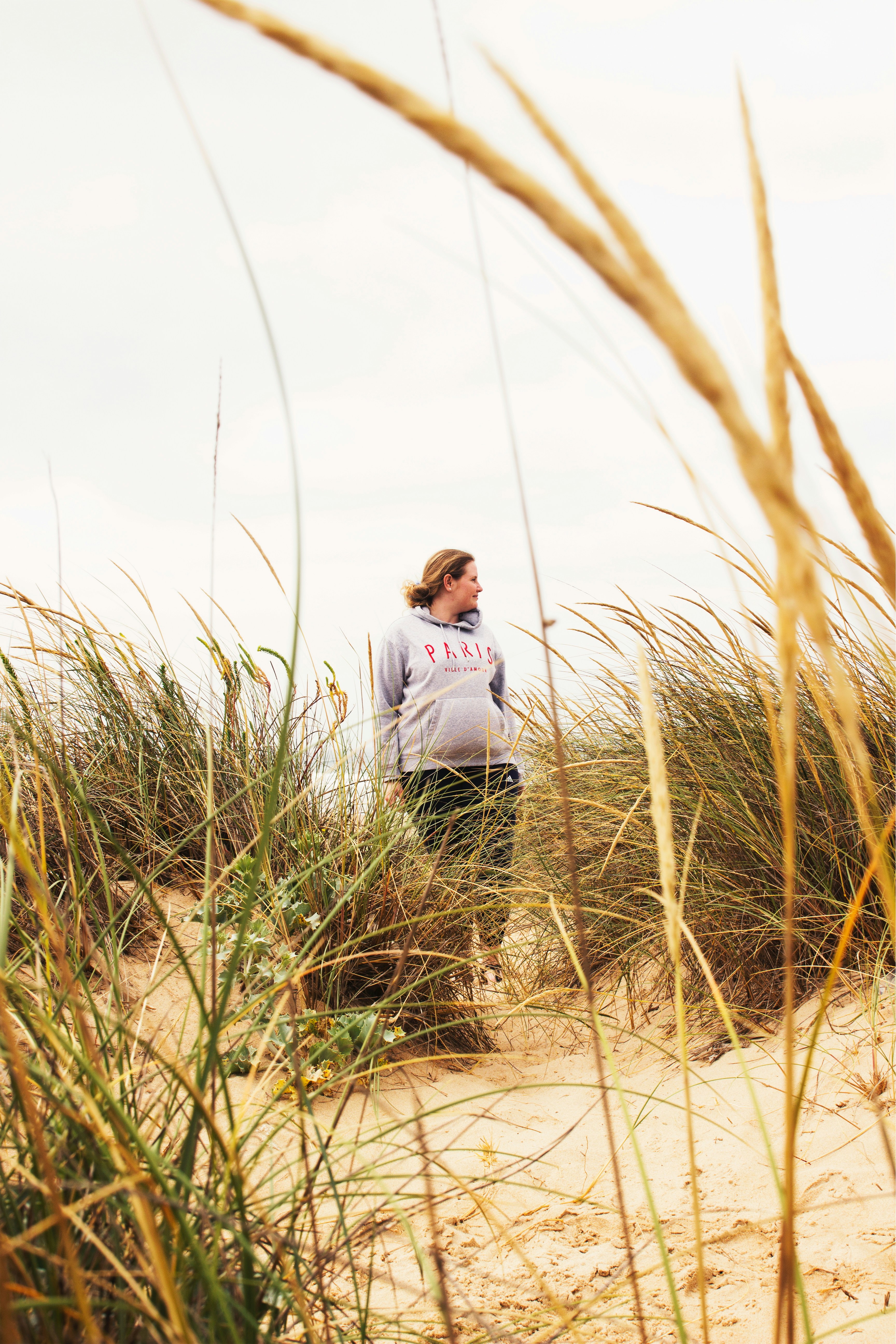 Woman standing in tall grass by the ocean