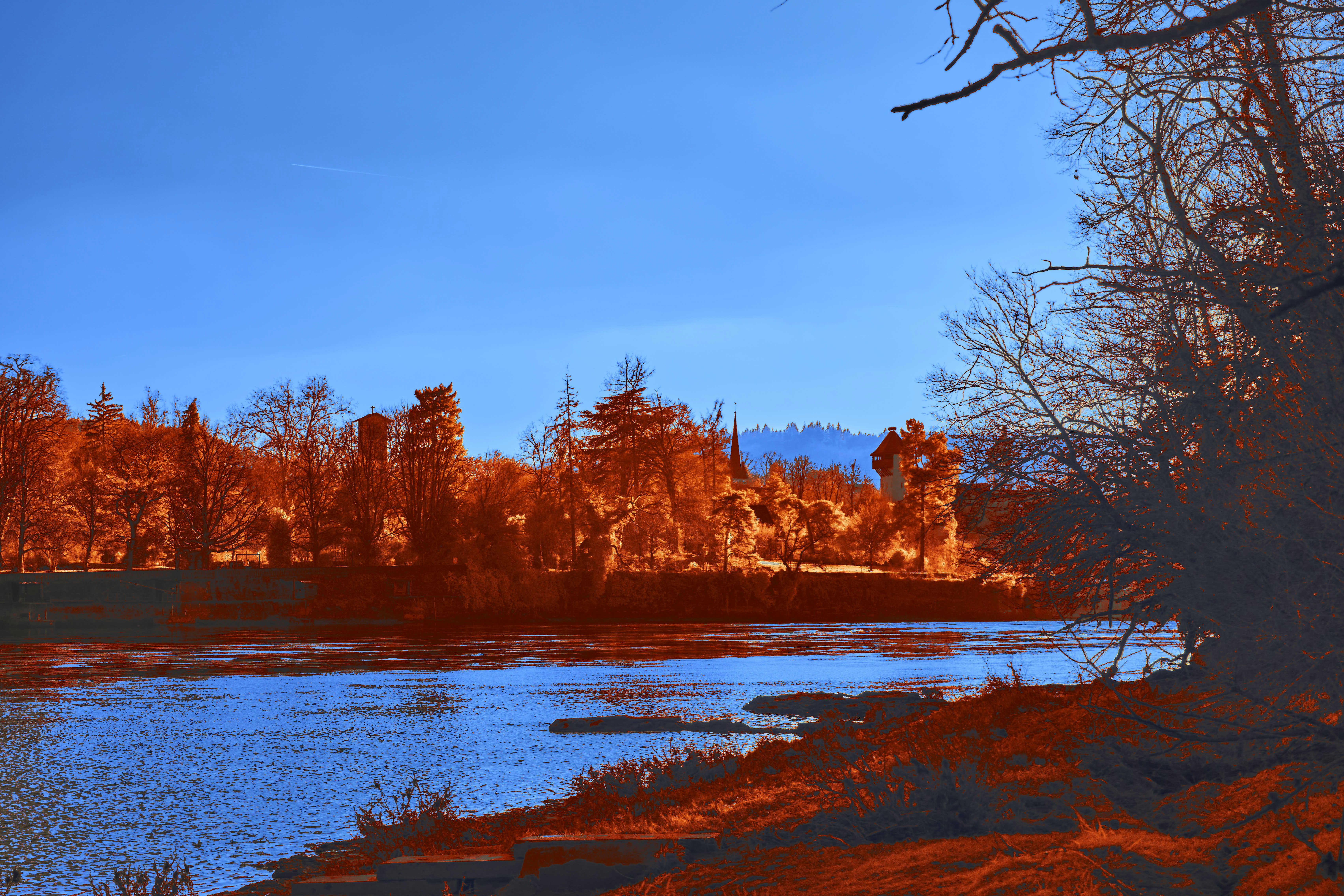 Bright blue sky over a river and autumn trees