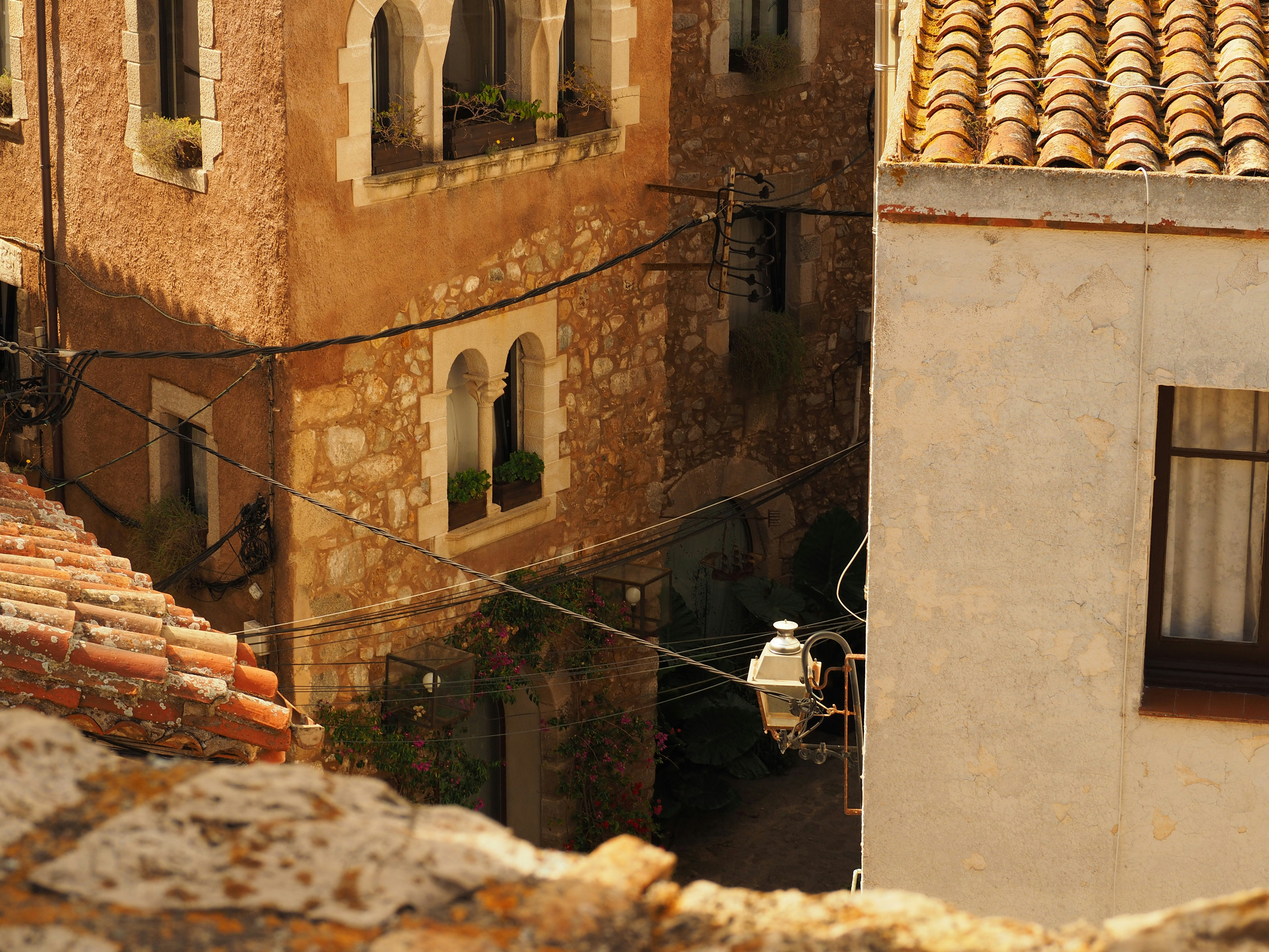 Lantern Over a Sunlit Courtyard Between Weathered Facades