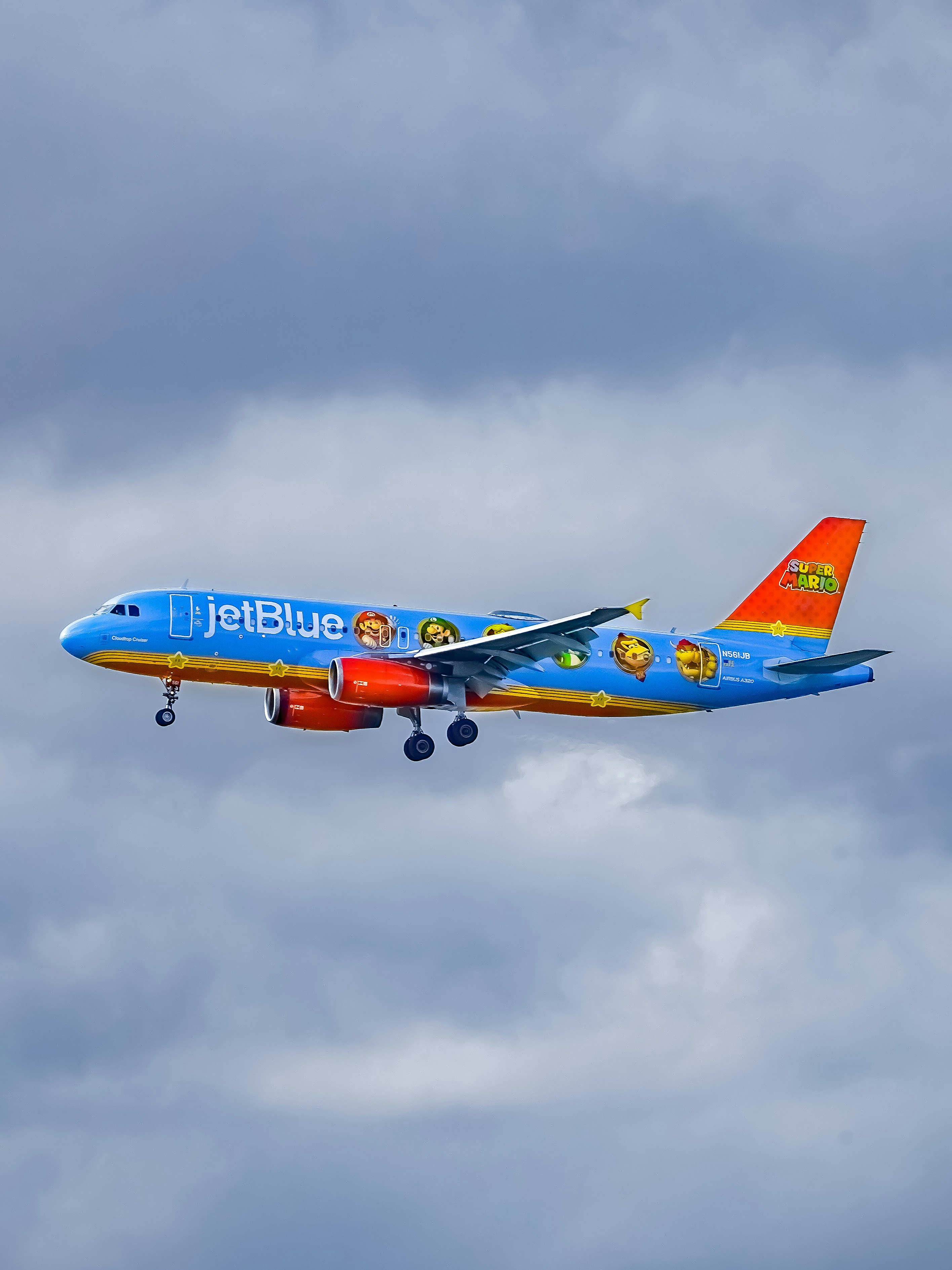 JetBlue aircraft adorned with vibrant characters gliding through a cloudy sky. The playful design adds a whimsical touch to air travel.