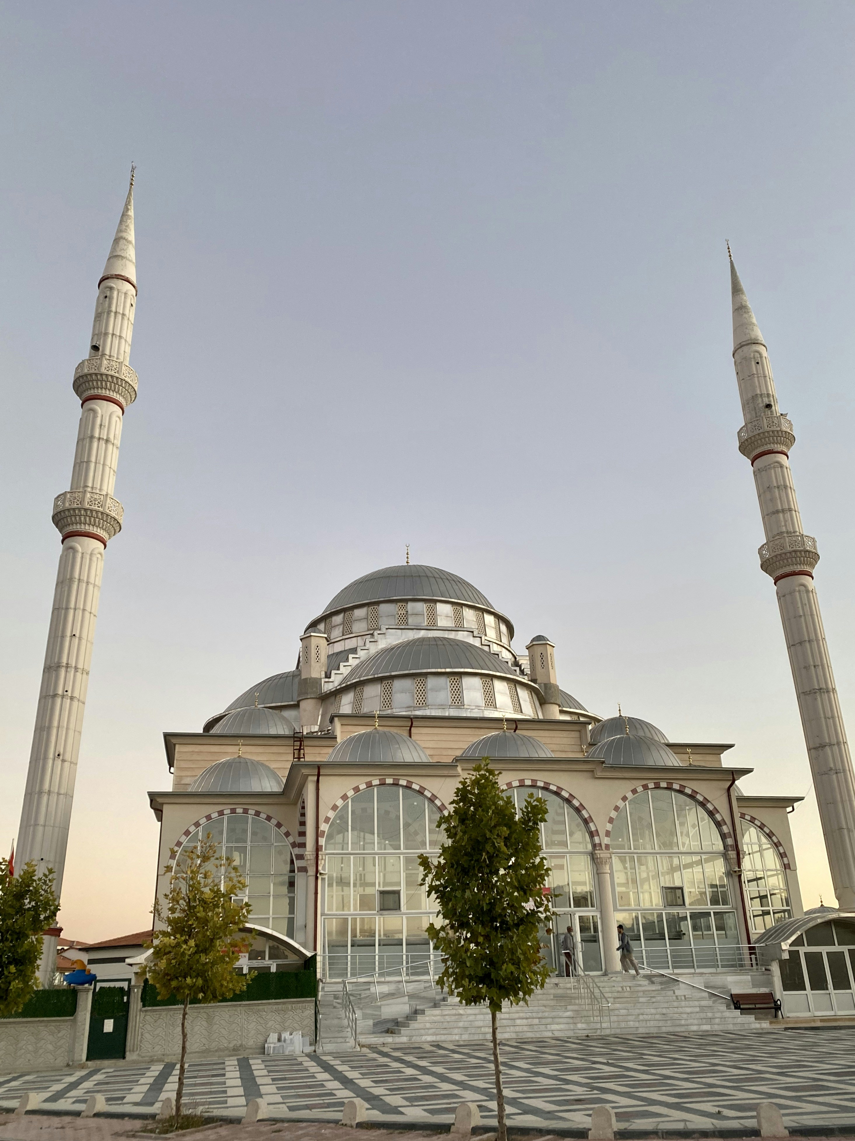 Grand mosque featuring intricate architecture with towering minarets and a large dome, set against a serene twilight backdrop.