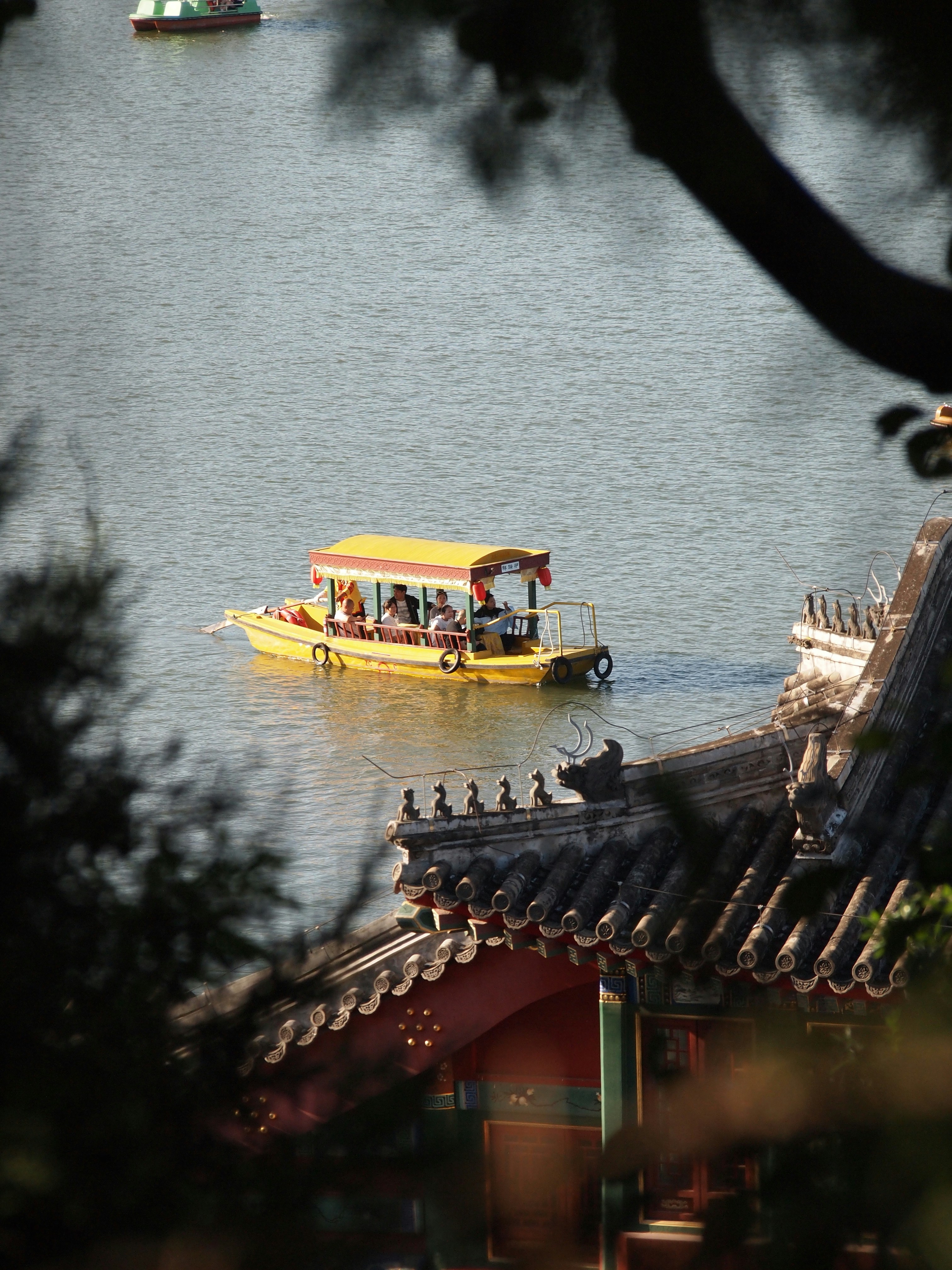 Yellow boat on a sunlit river framed by ornate pavilion roofs