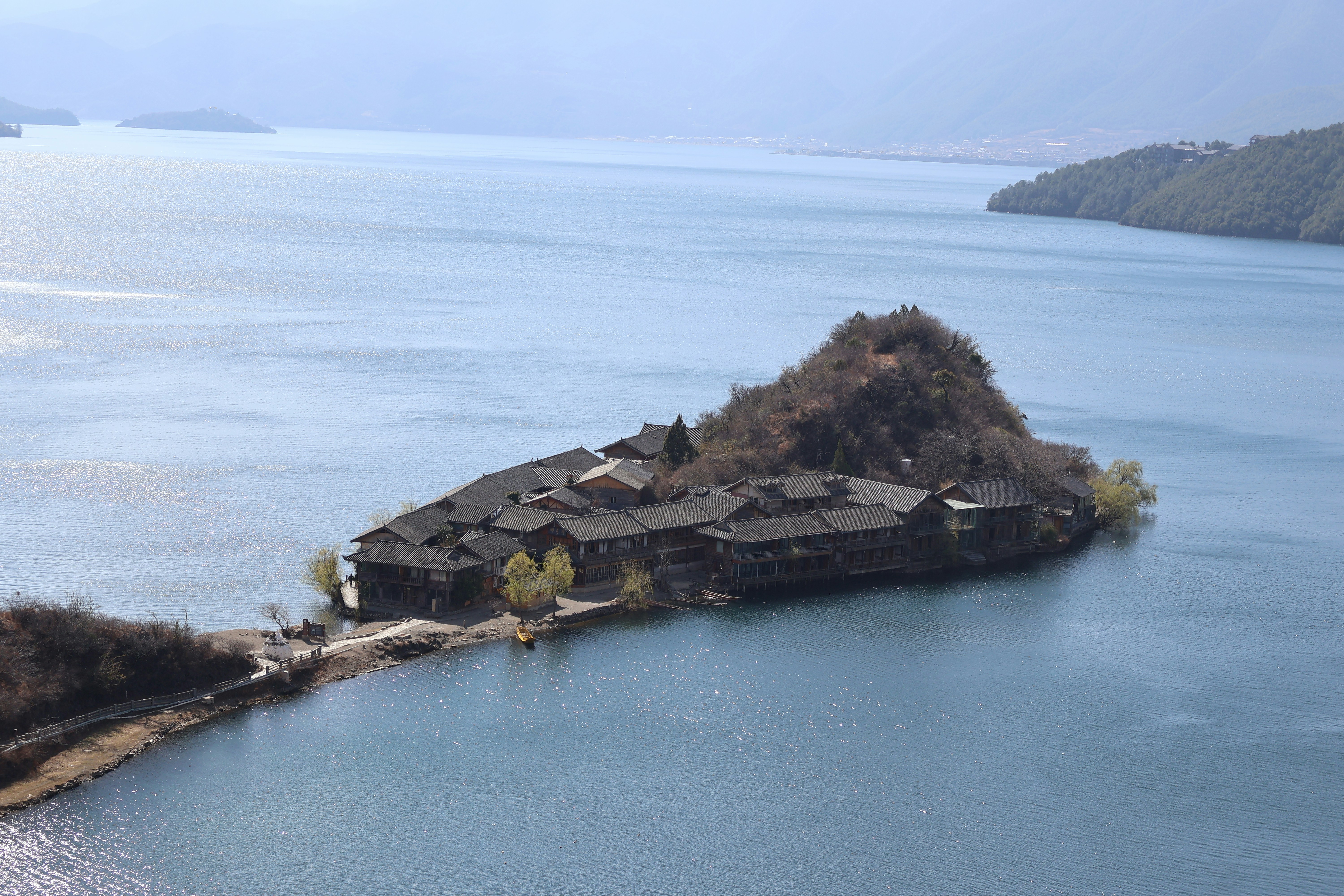 Lige Peninsula on Lugu Lake, a stunning alpine lake on the border of Yunnan and Sichuan provinces in China | Buildings nestled on a small island in a vast lake.