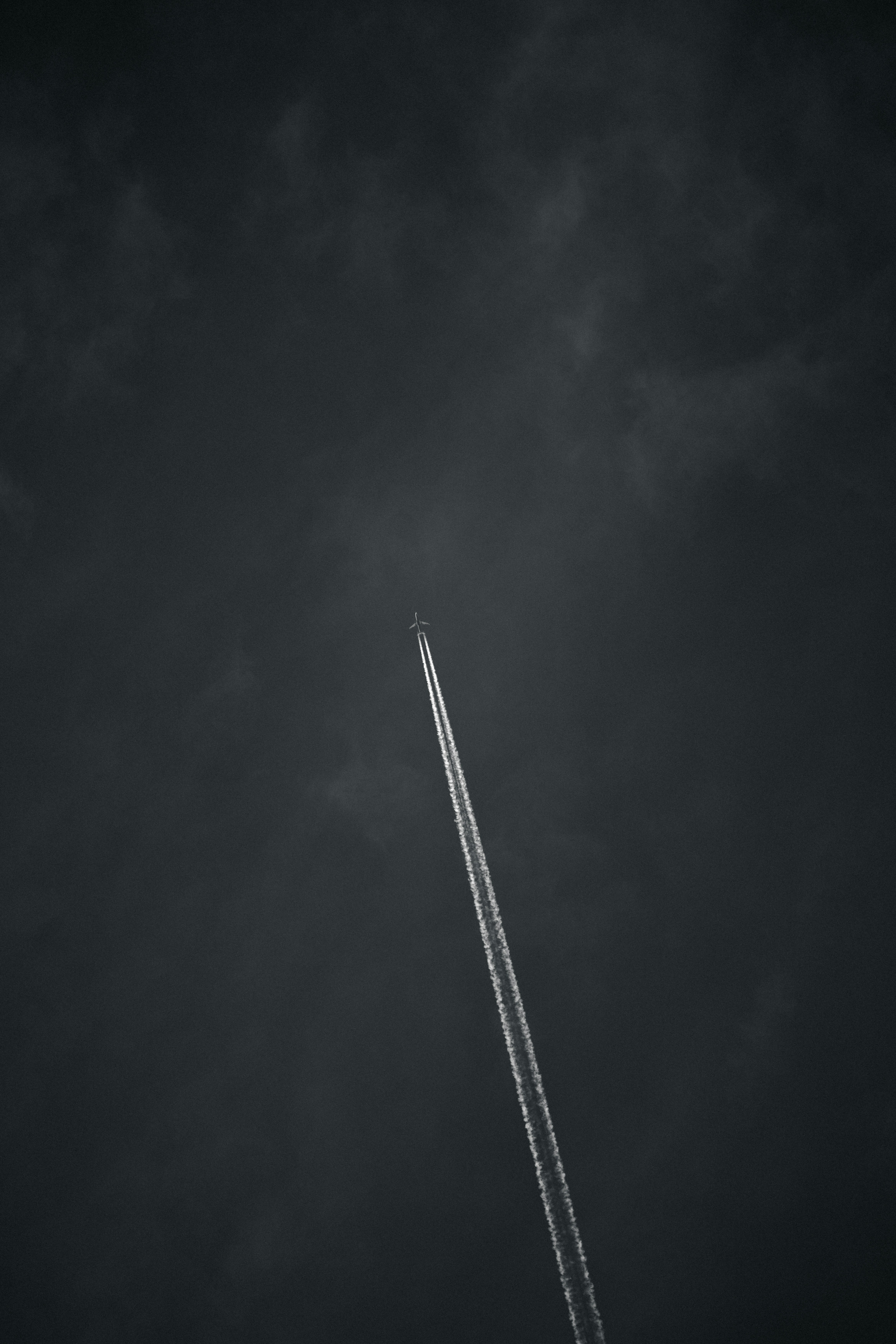 Airplane leaving a contrail against a dark sky