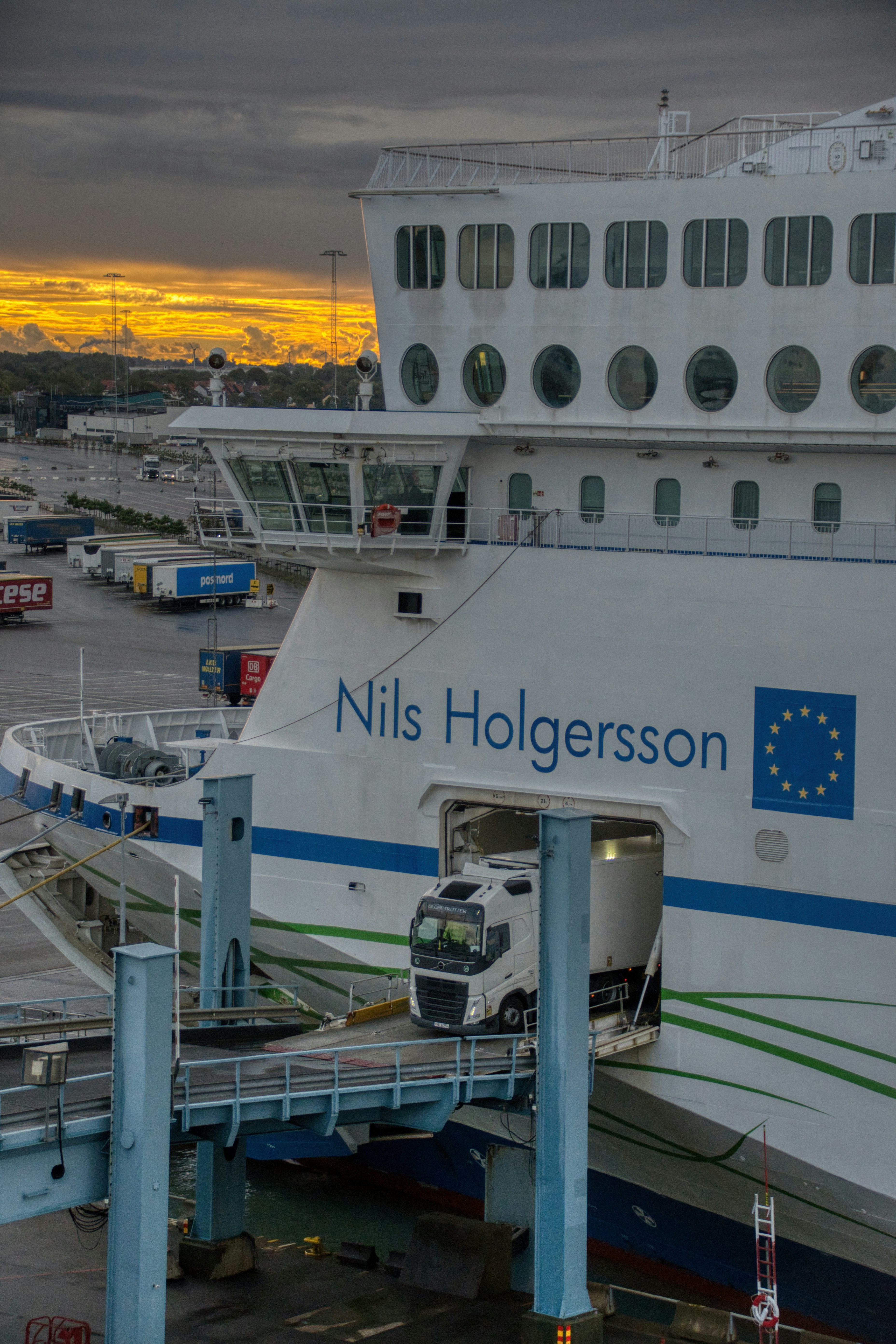 Truck drives onto nils holgersson ferry at sunset.