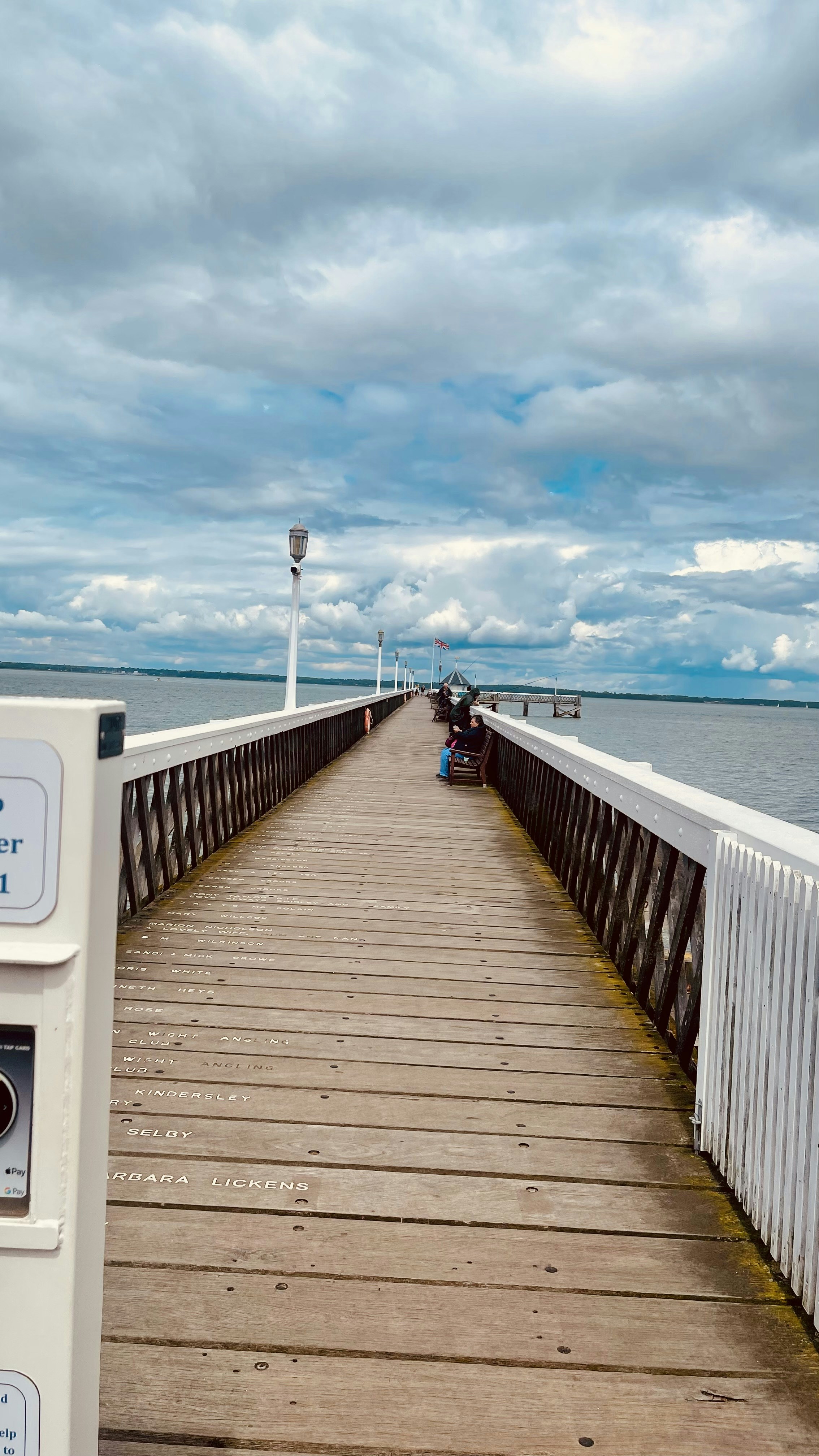 Wooden pier stretching into the calm sea under cloudy sky