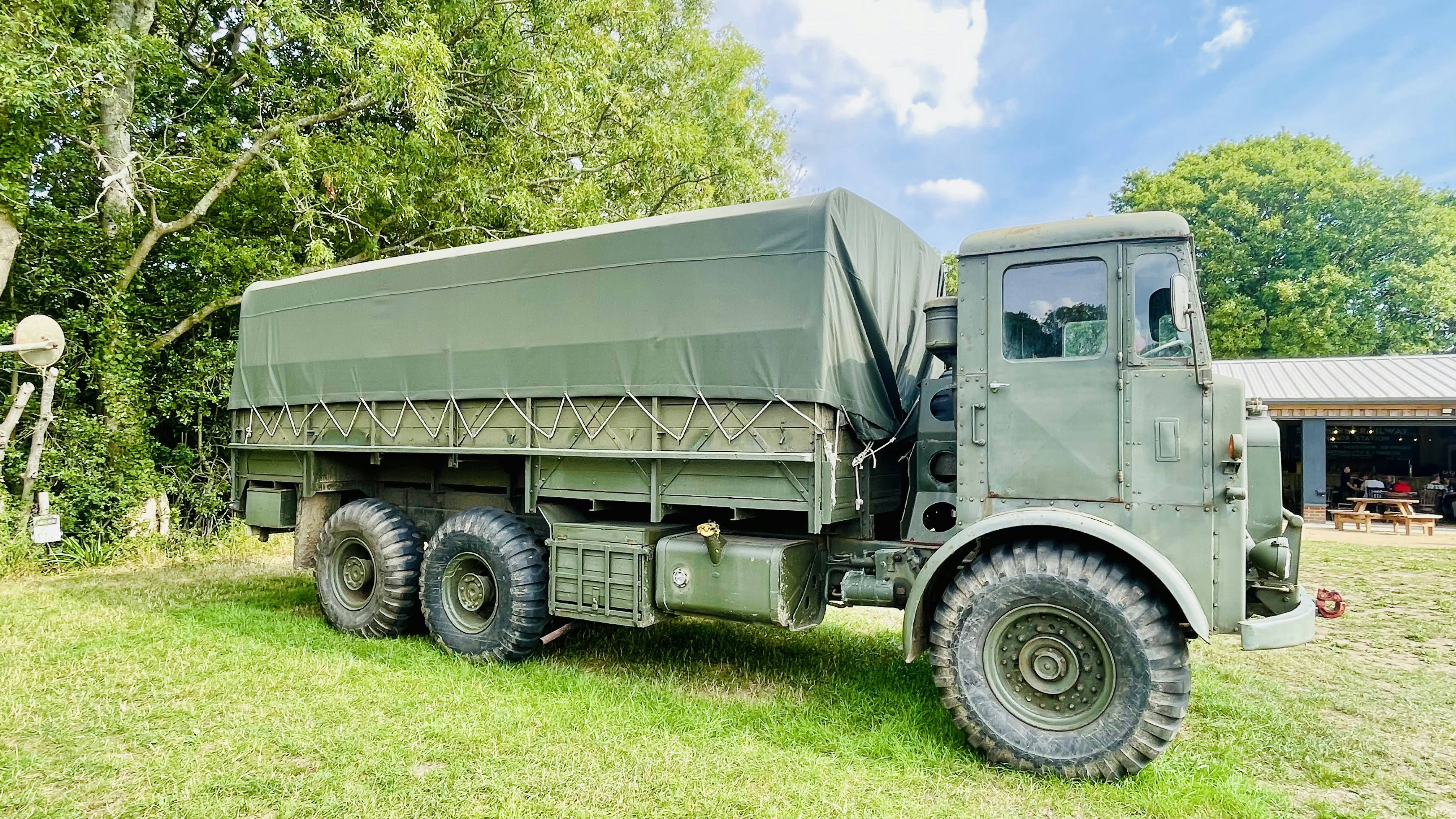 A green military truck with a covered cargo bed.
