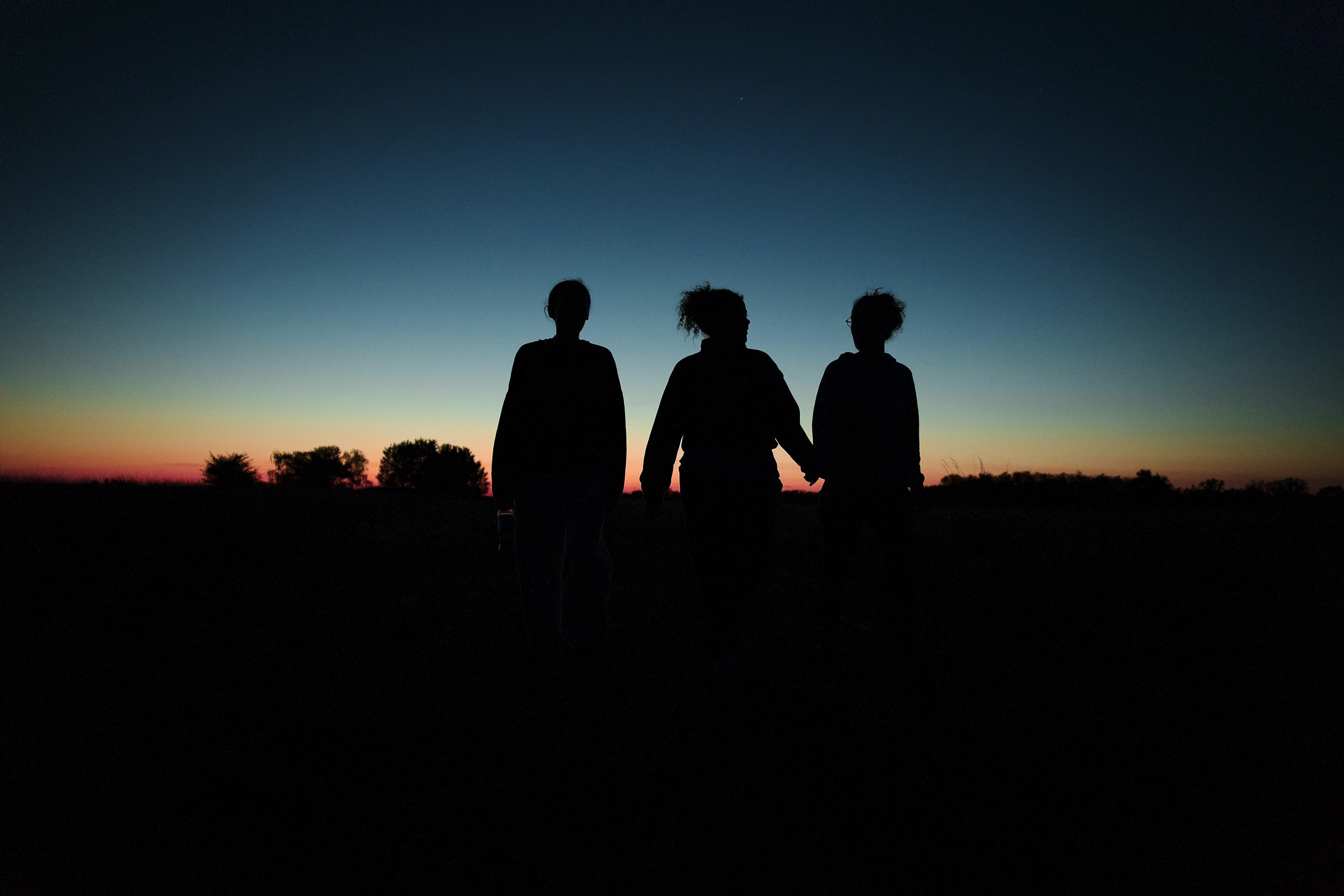 Trio at the Horizon: silhouettes against a fading sky