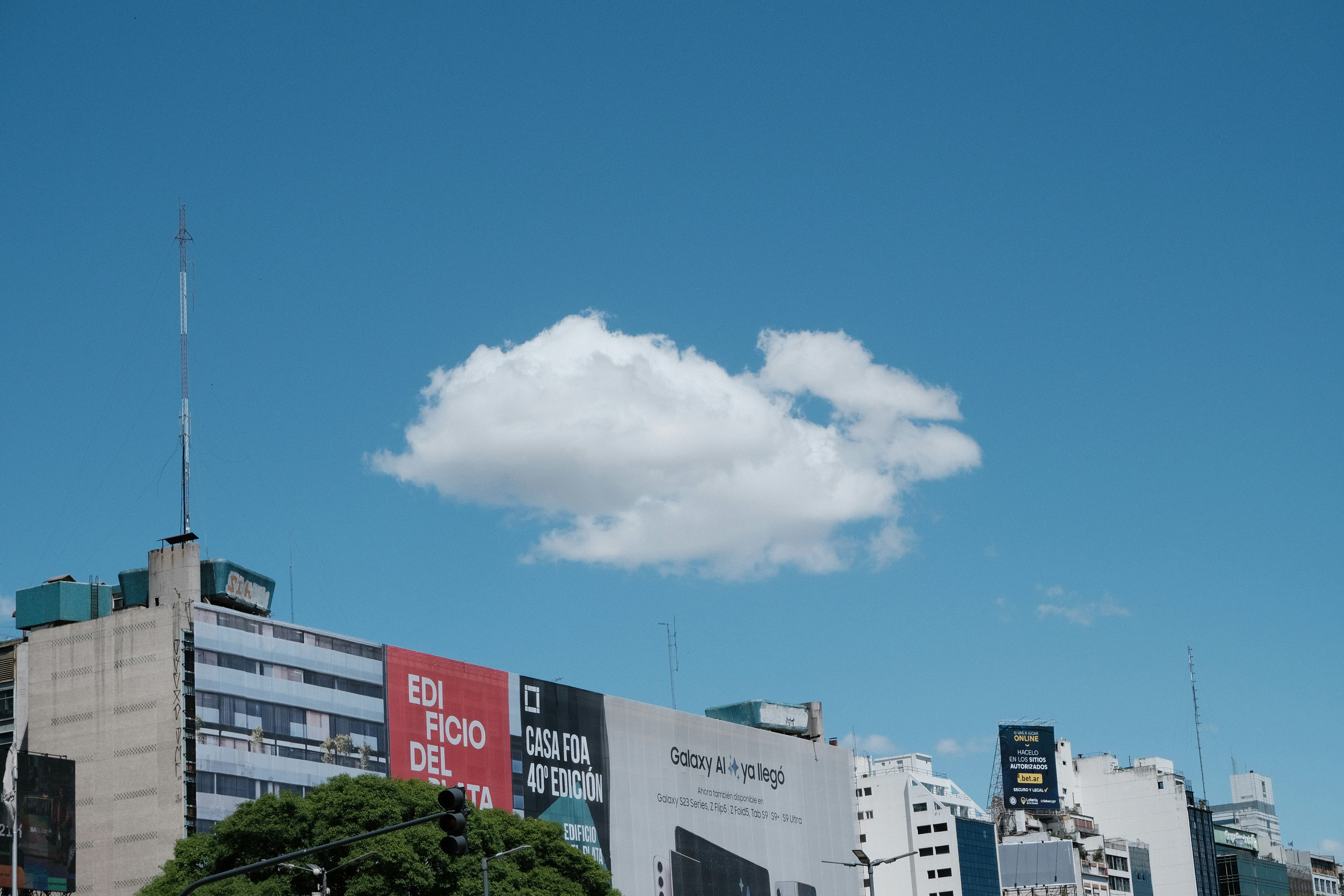 A single white cloud floats over city buildings.