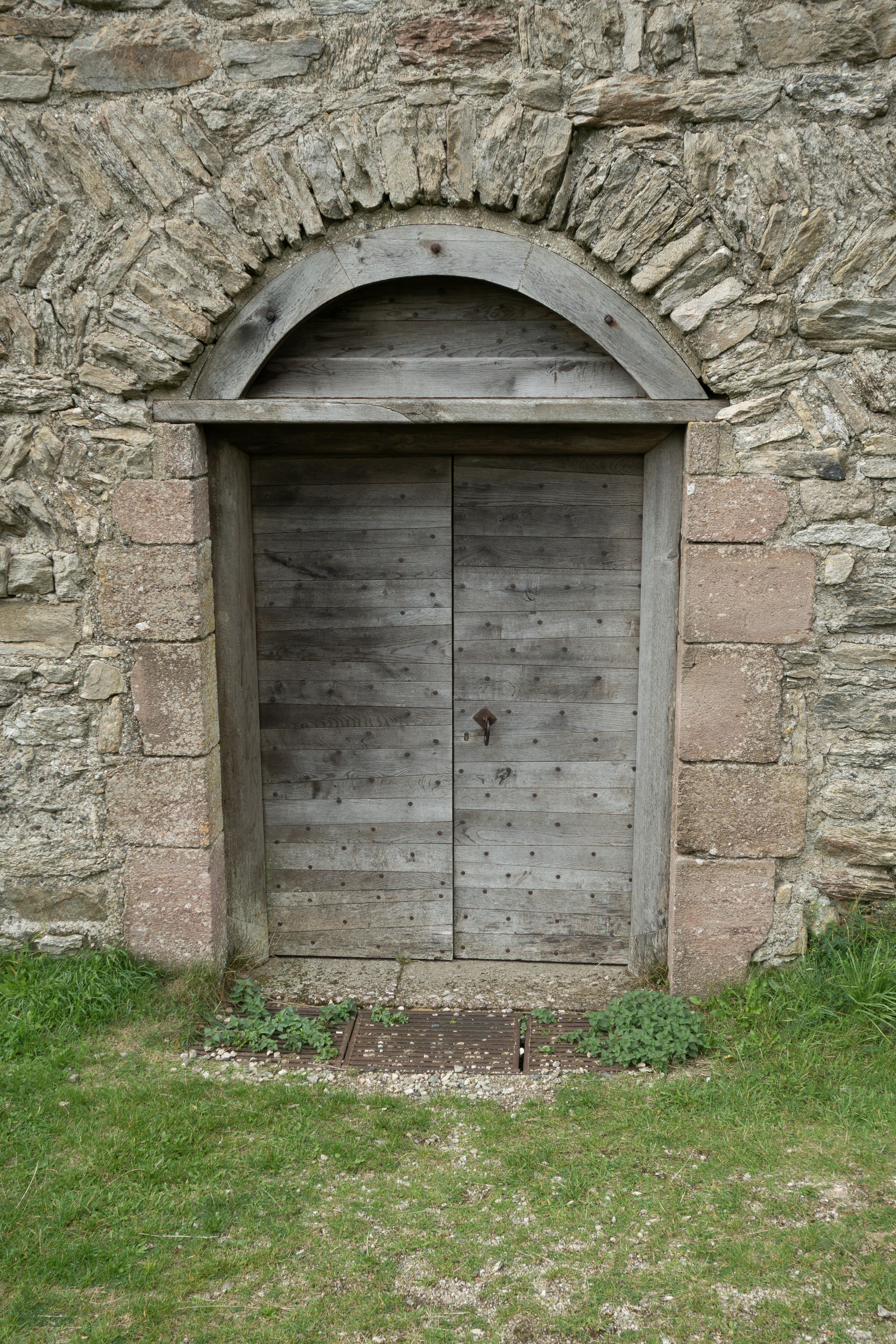 Sur ce chemin, l’homme ne conquiert rien. Il écoute. Il marche entre les pierres et les nuages, là où Stevenson jadis chercha le silence et la vérité. Chaque pas est une mémoire, chaque paysage une page ouverte. Ce n’est pas la France qu’on traverse, mais un monde en miniature — fait de lumière, de solitude, et d rencontres. | Rustic wooden doors set in stone wall