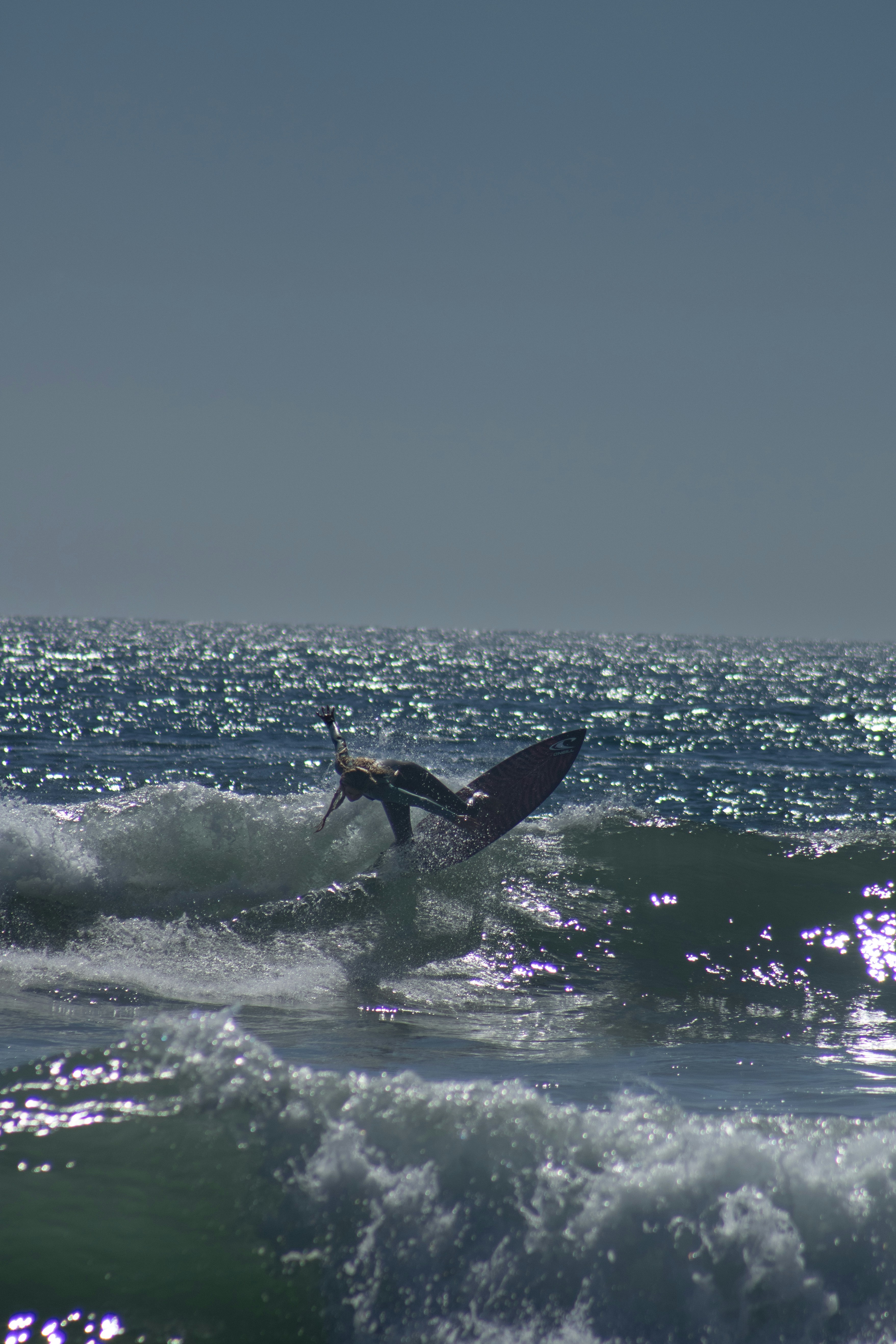 Glint on the Glide: Surfer Carves a Sunlit Break