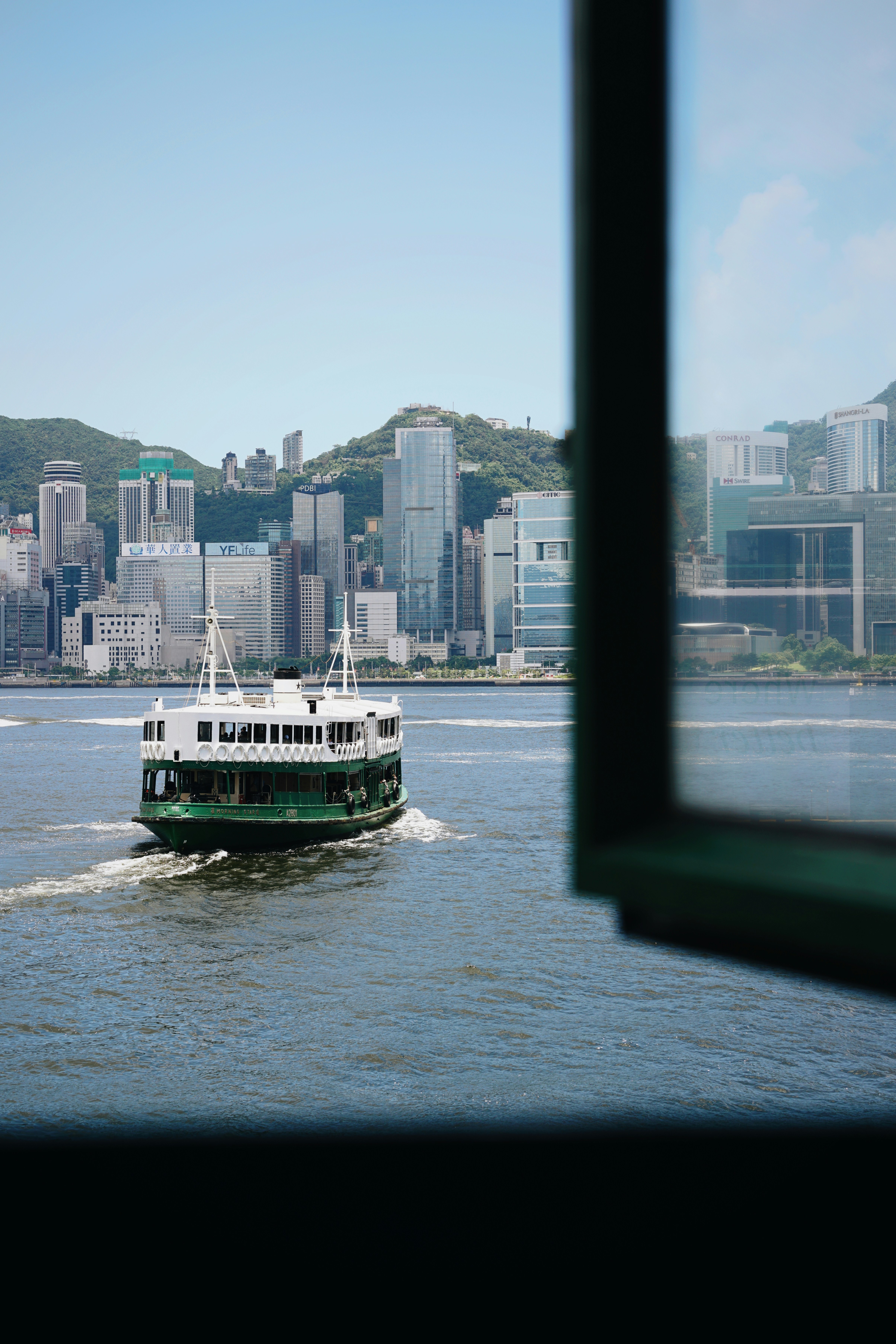 Ferry boat travels across water towards city skyline.