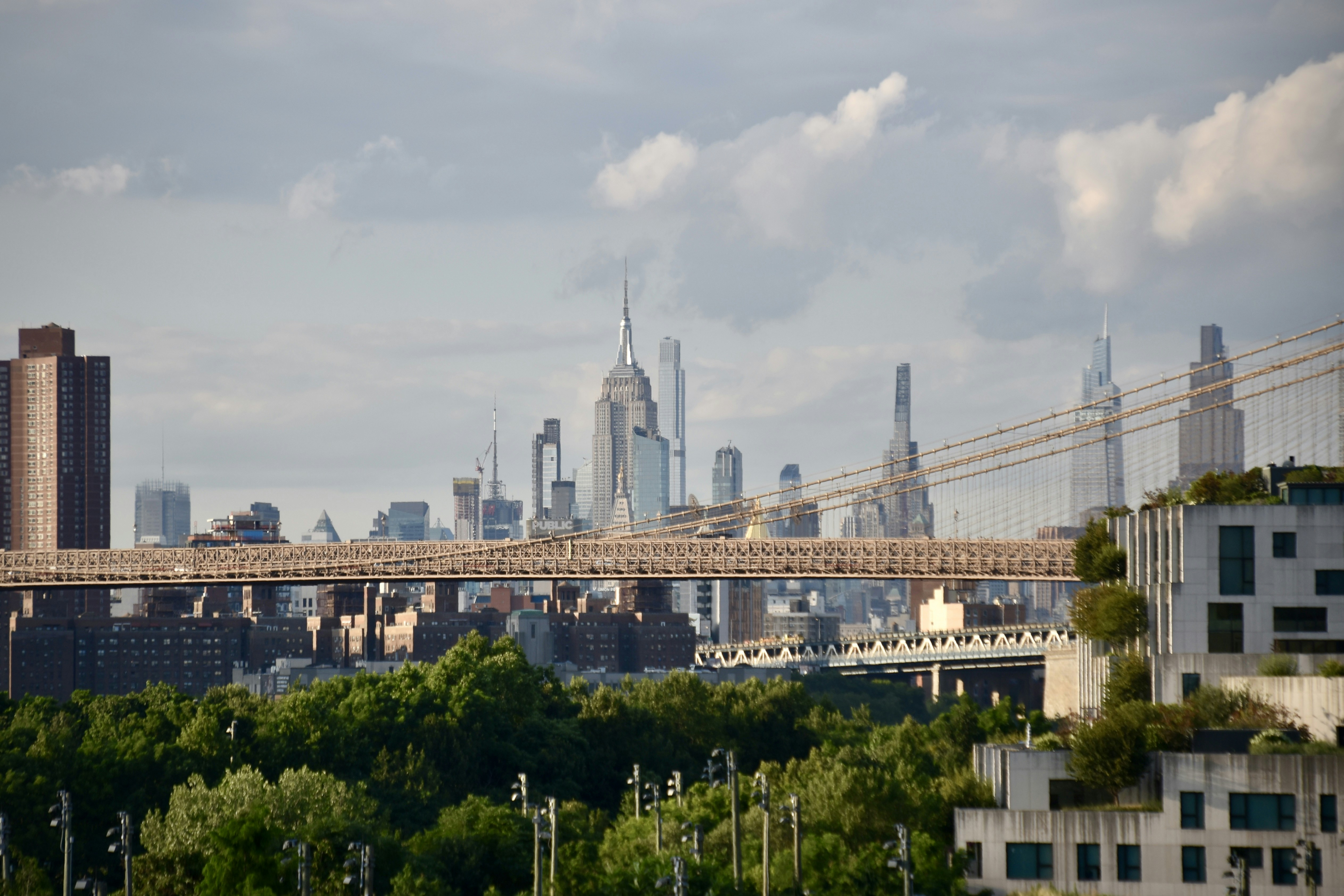 Looking at Midtown Manhattan from Brooklyn heights | City skyline with bridge and green trees