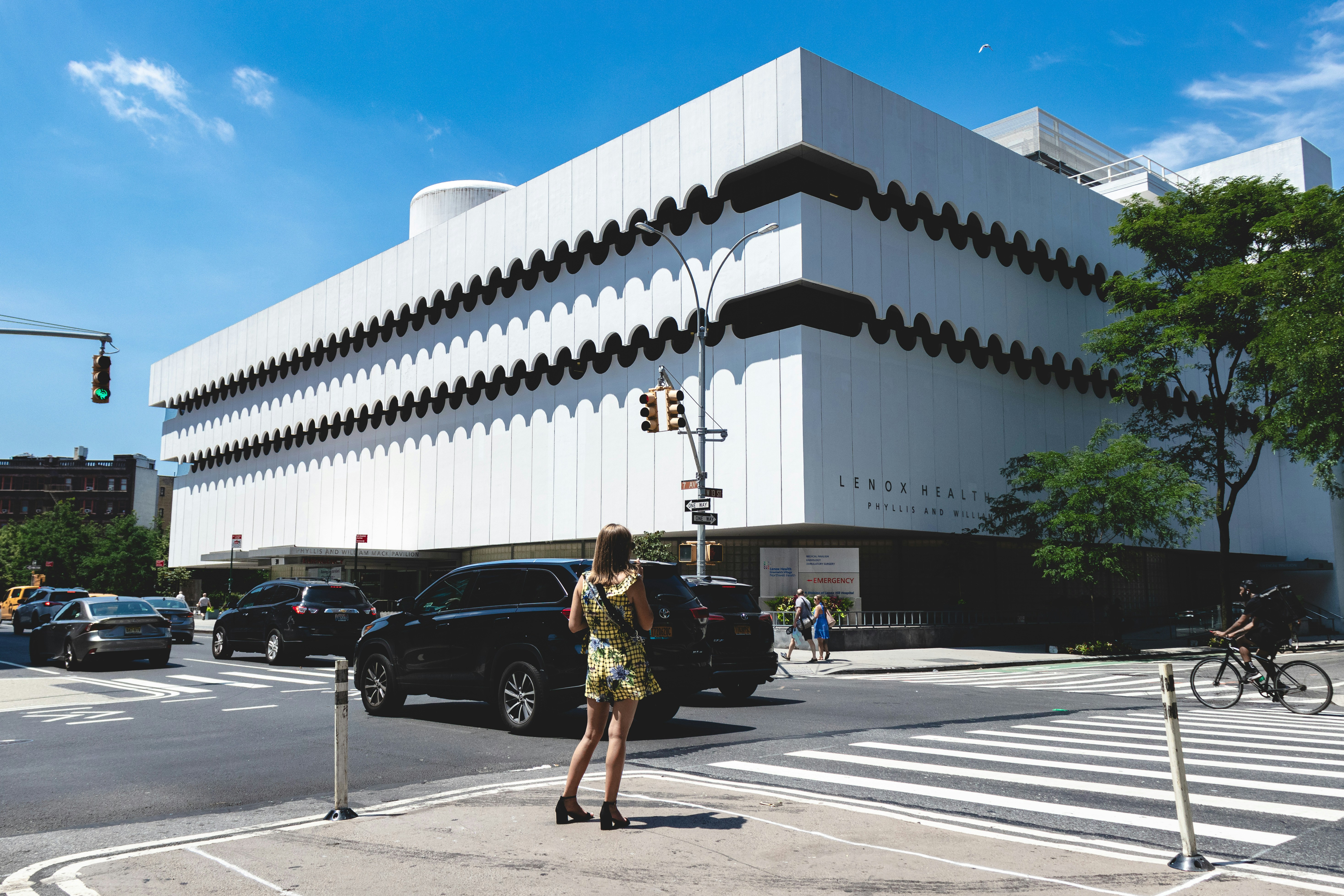Modern architectural structure with distinctive black and white design, featuring a pedestrian on the street in a floral dress.