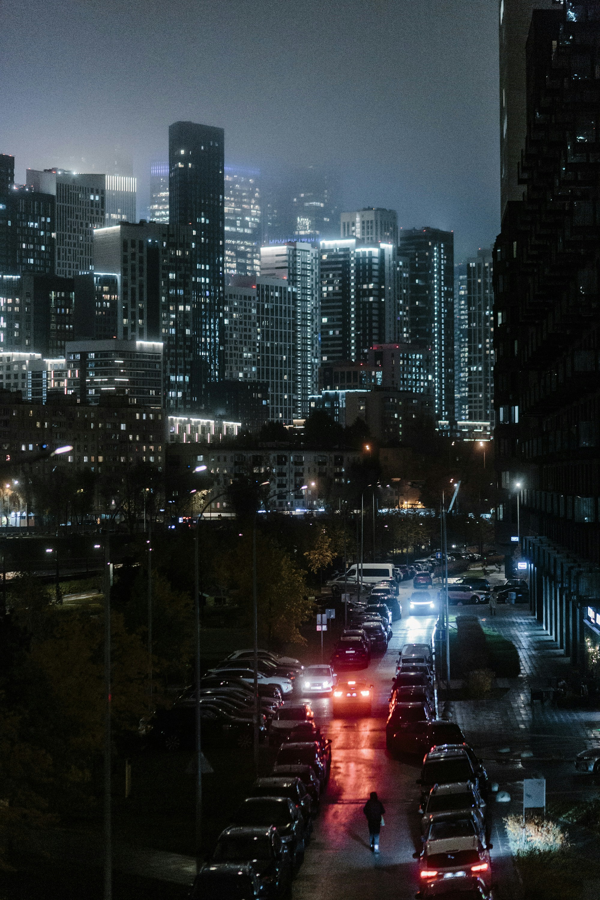 Rainy night cityscape with glowing skyscrapers and cars.