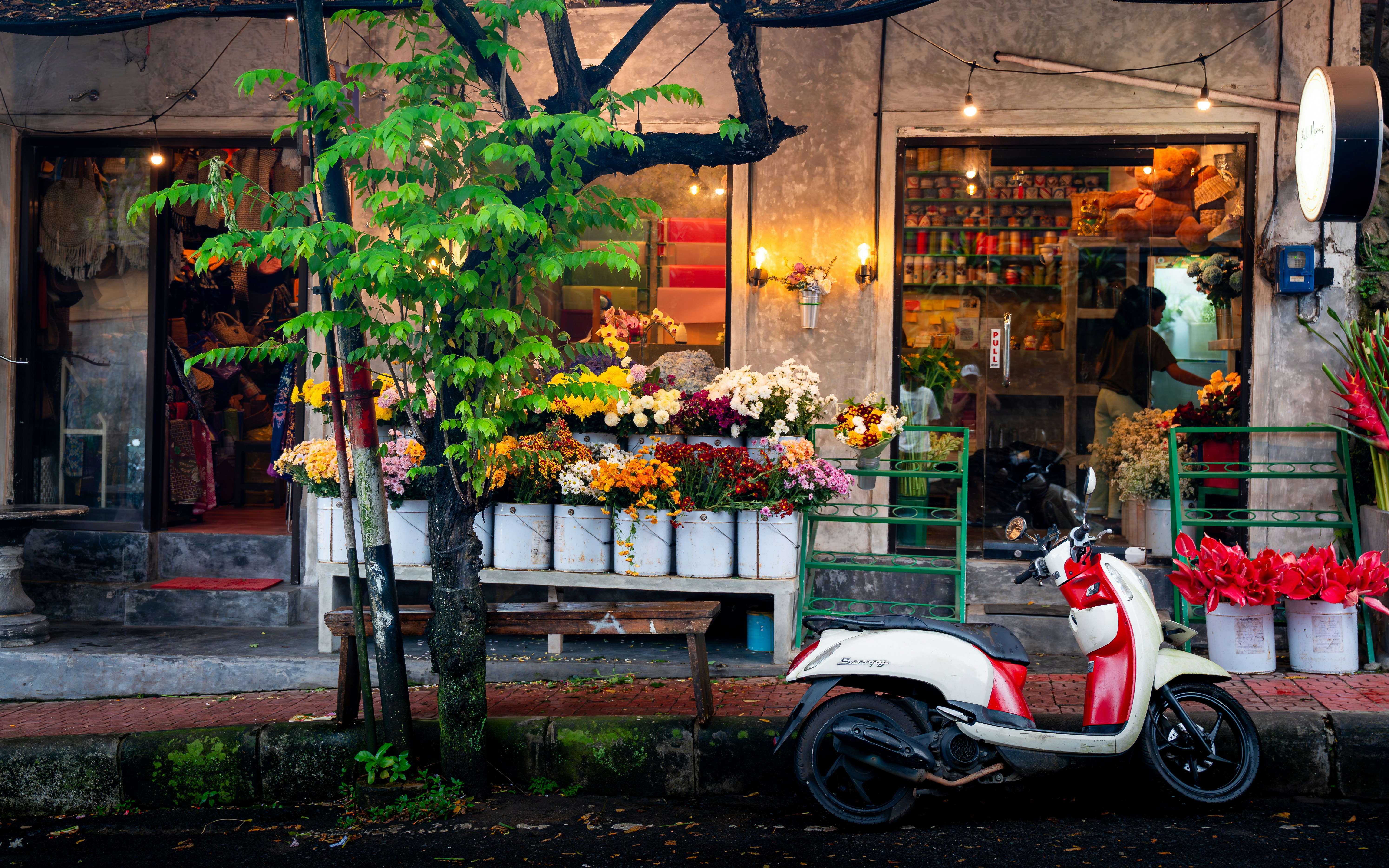 Scooter parked by a flower shop on a street
