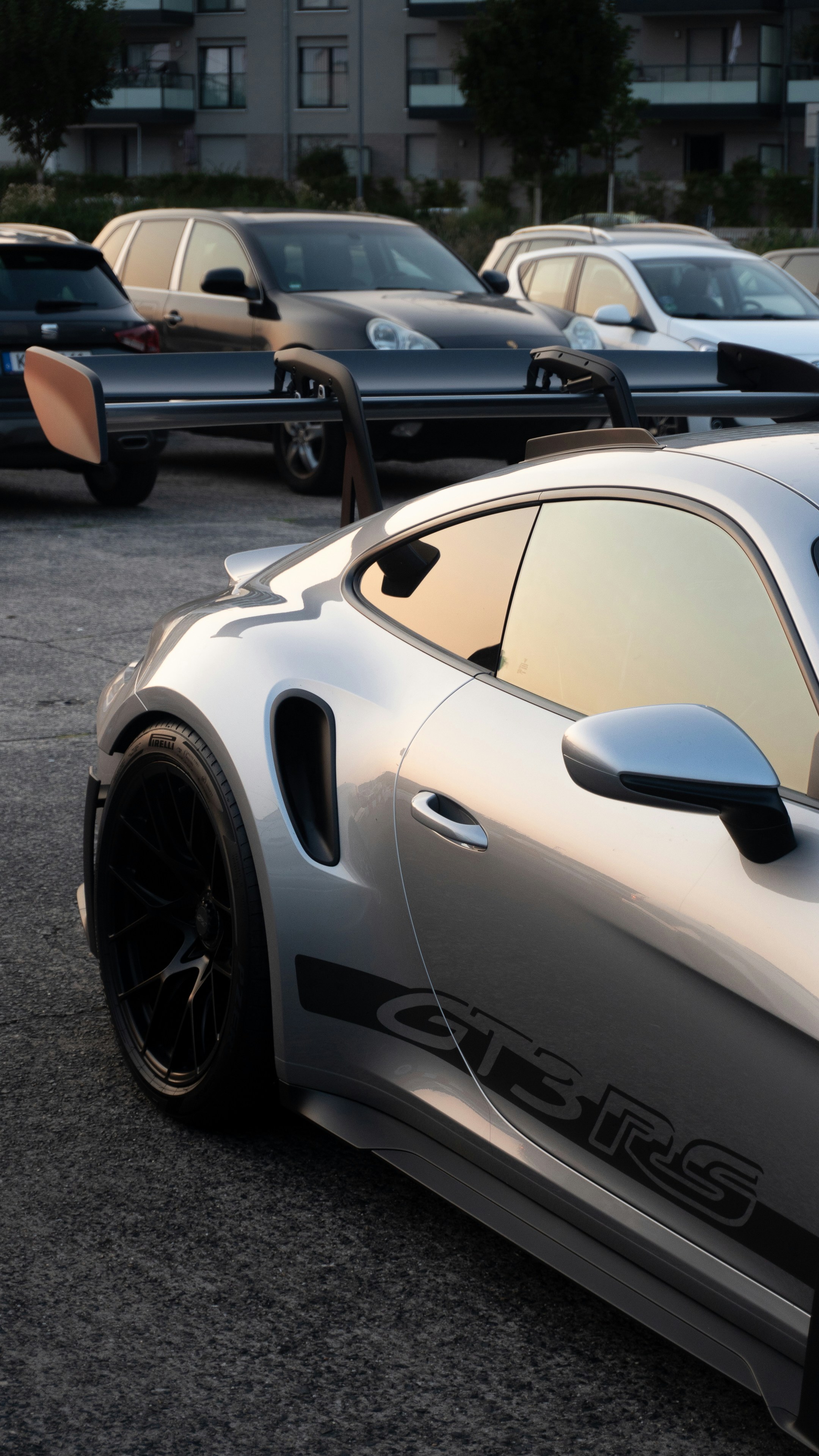 Silver porsche gt3 rs parked with other cars.