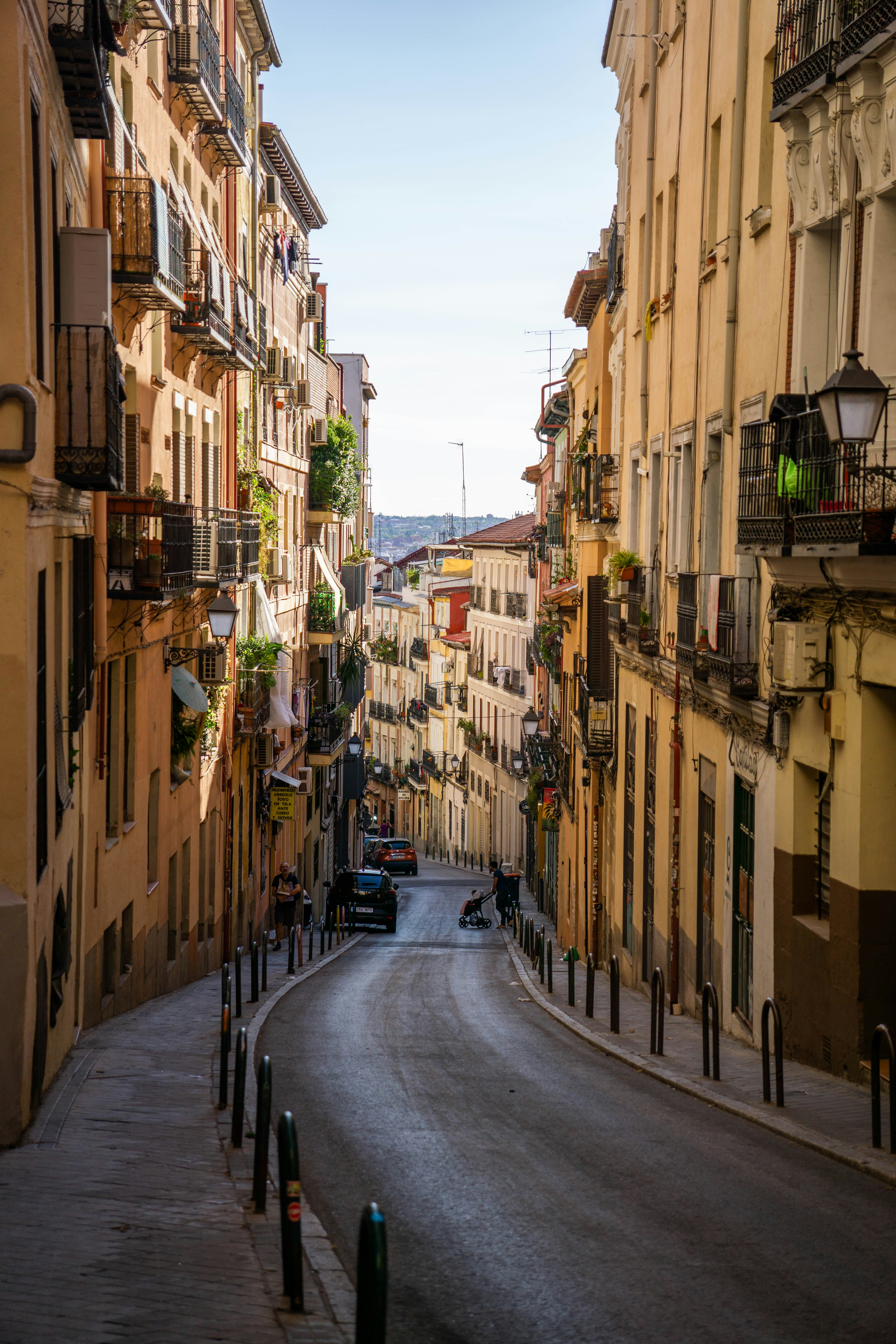 A quiet street going downhill, capturing the charm of Madrid’s neighborhoods. | Narrow street lined with old buildings in a city.