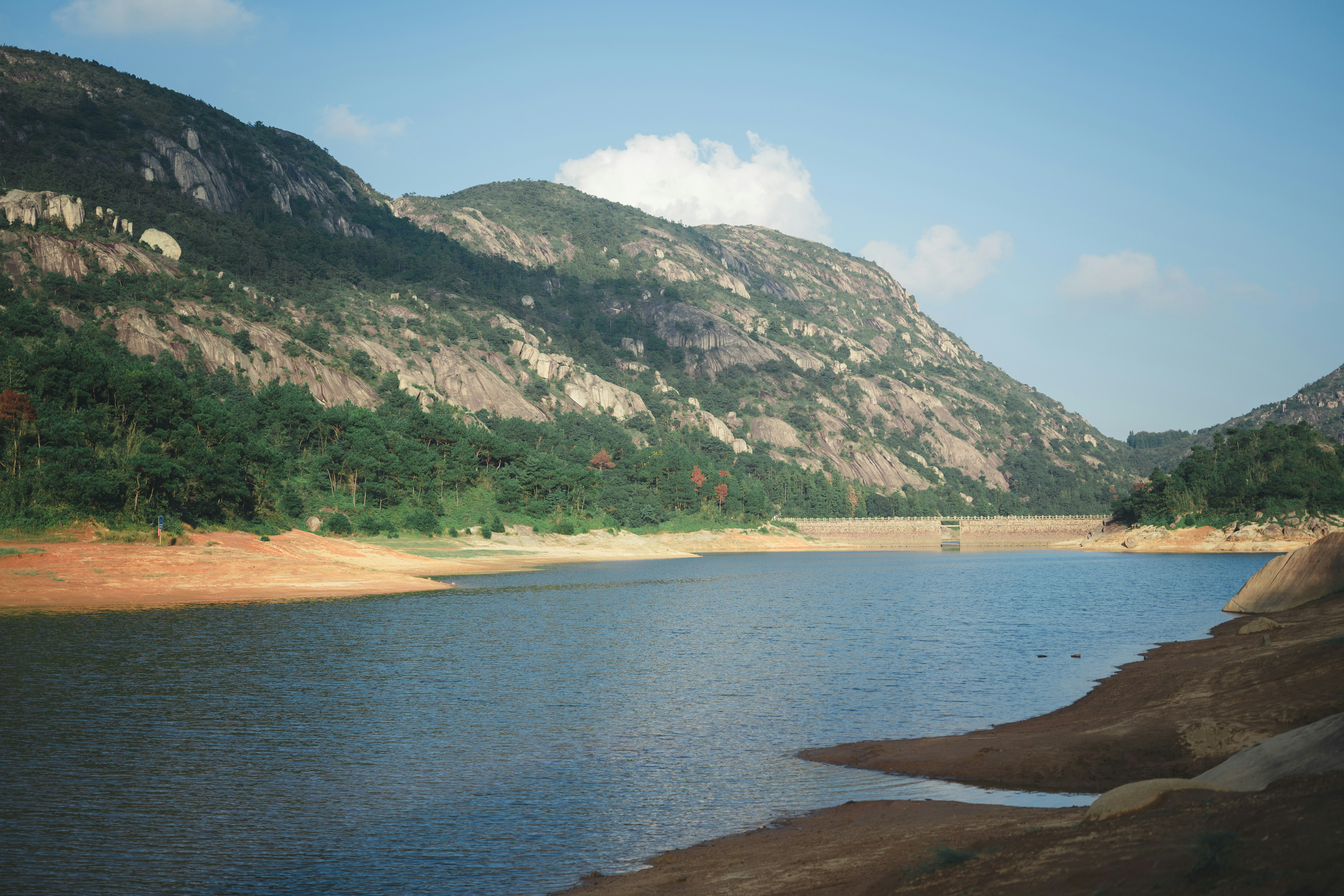 A calm lake surrounded by rocky, tree-covered mountains.