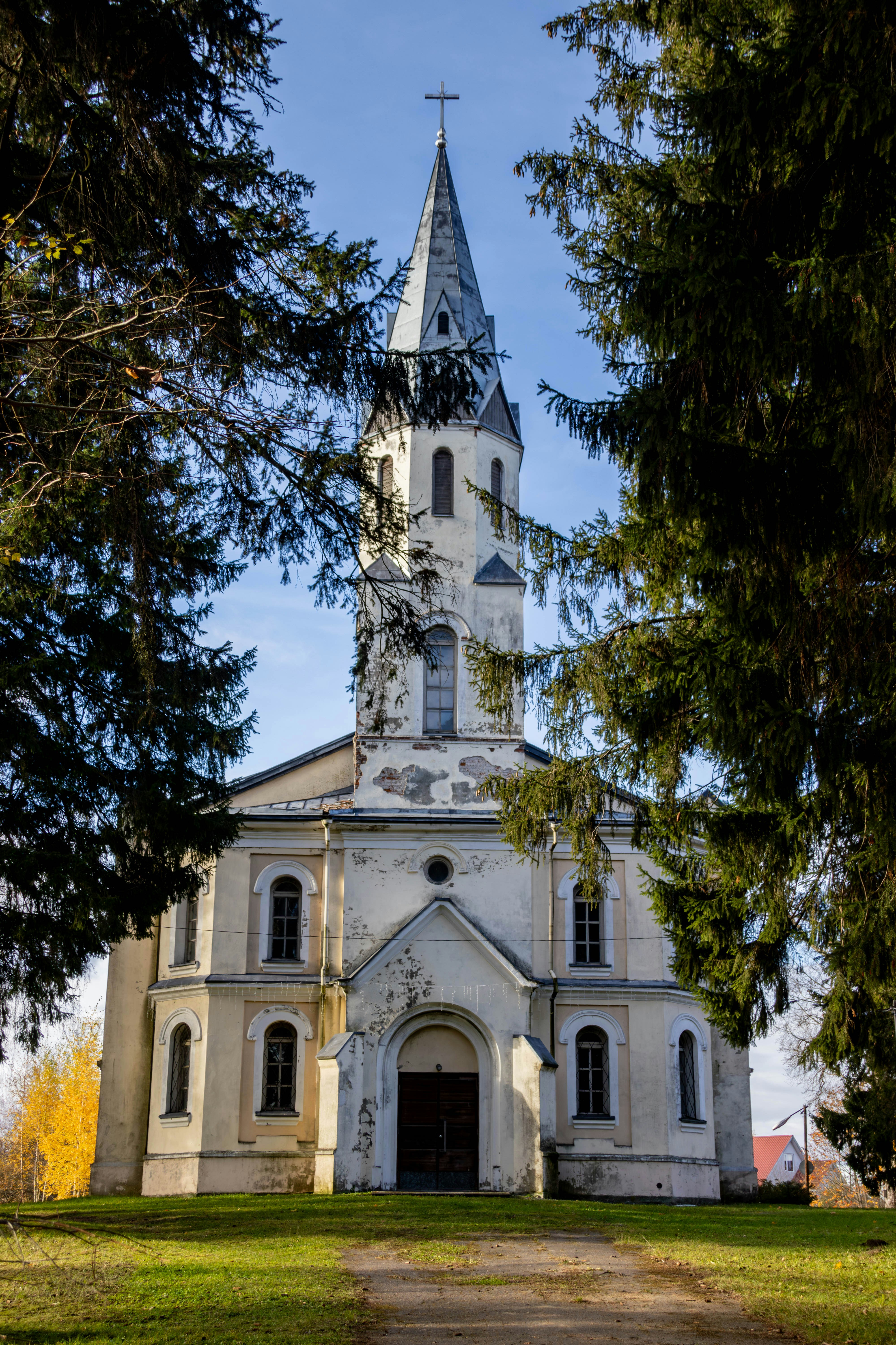 Church | A tall white church with a spire framed by trees.