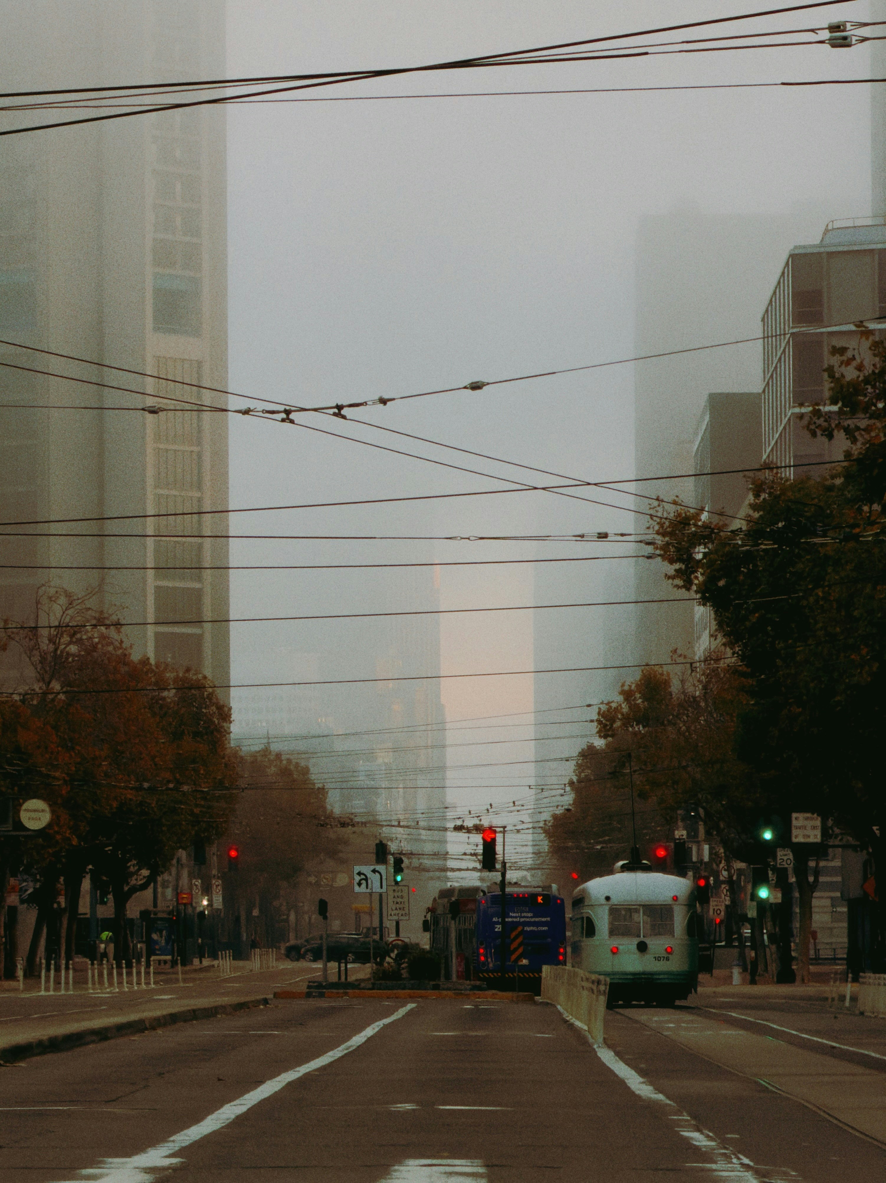 Foggy city street with buildings and tram.