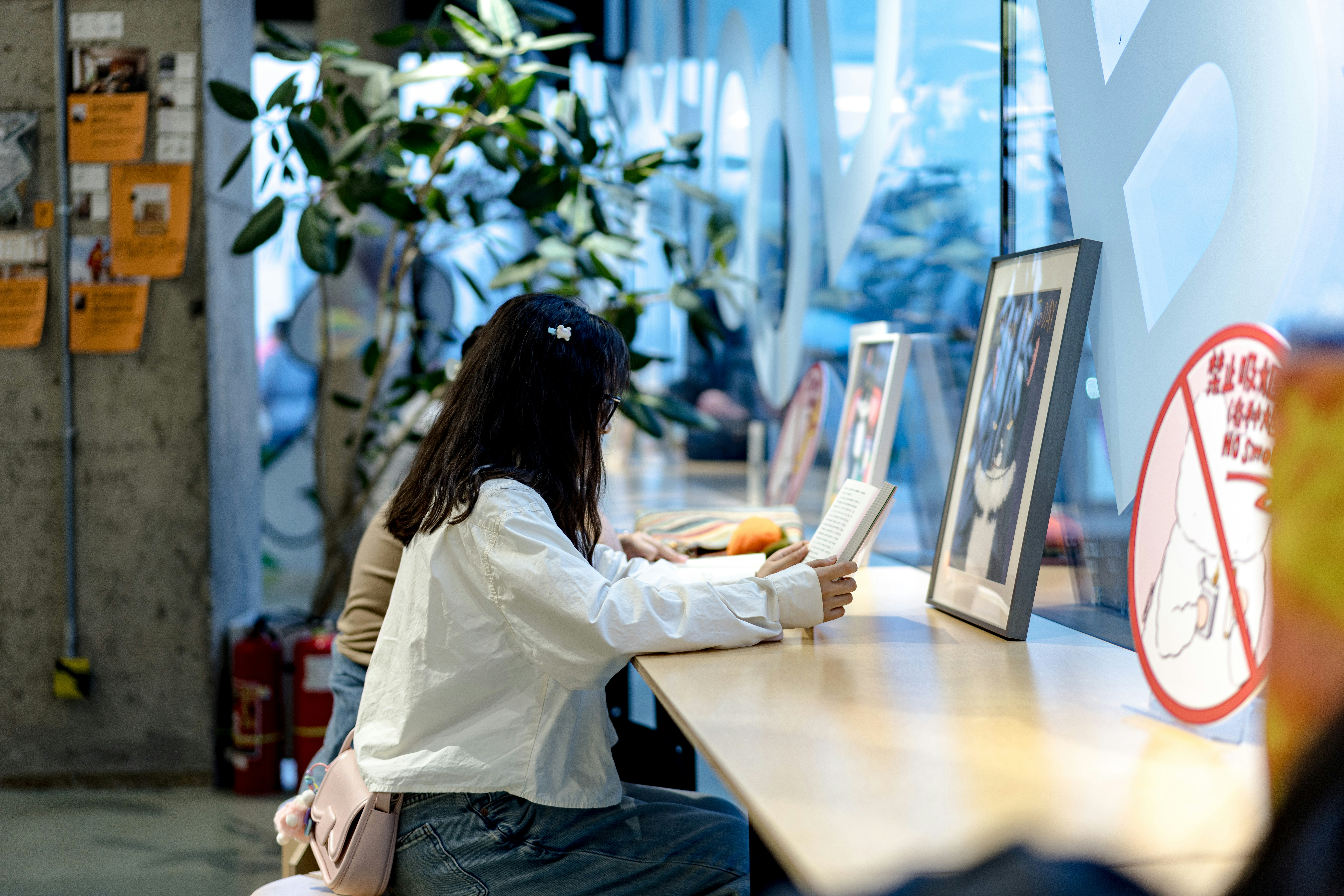Young woman reading a book at a wooden table.