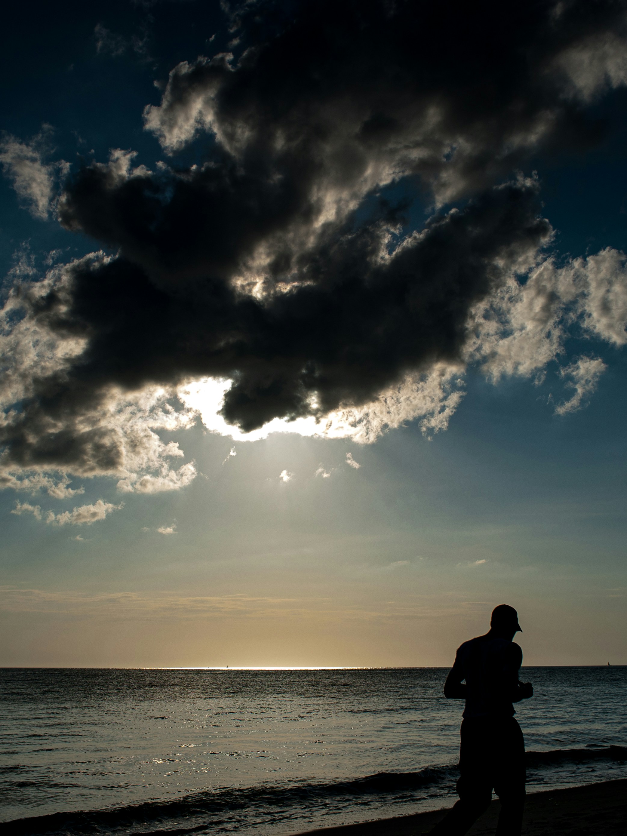 Silhouette of a man running on a beach at sunset.