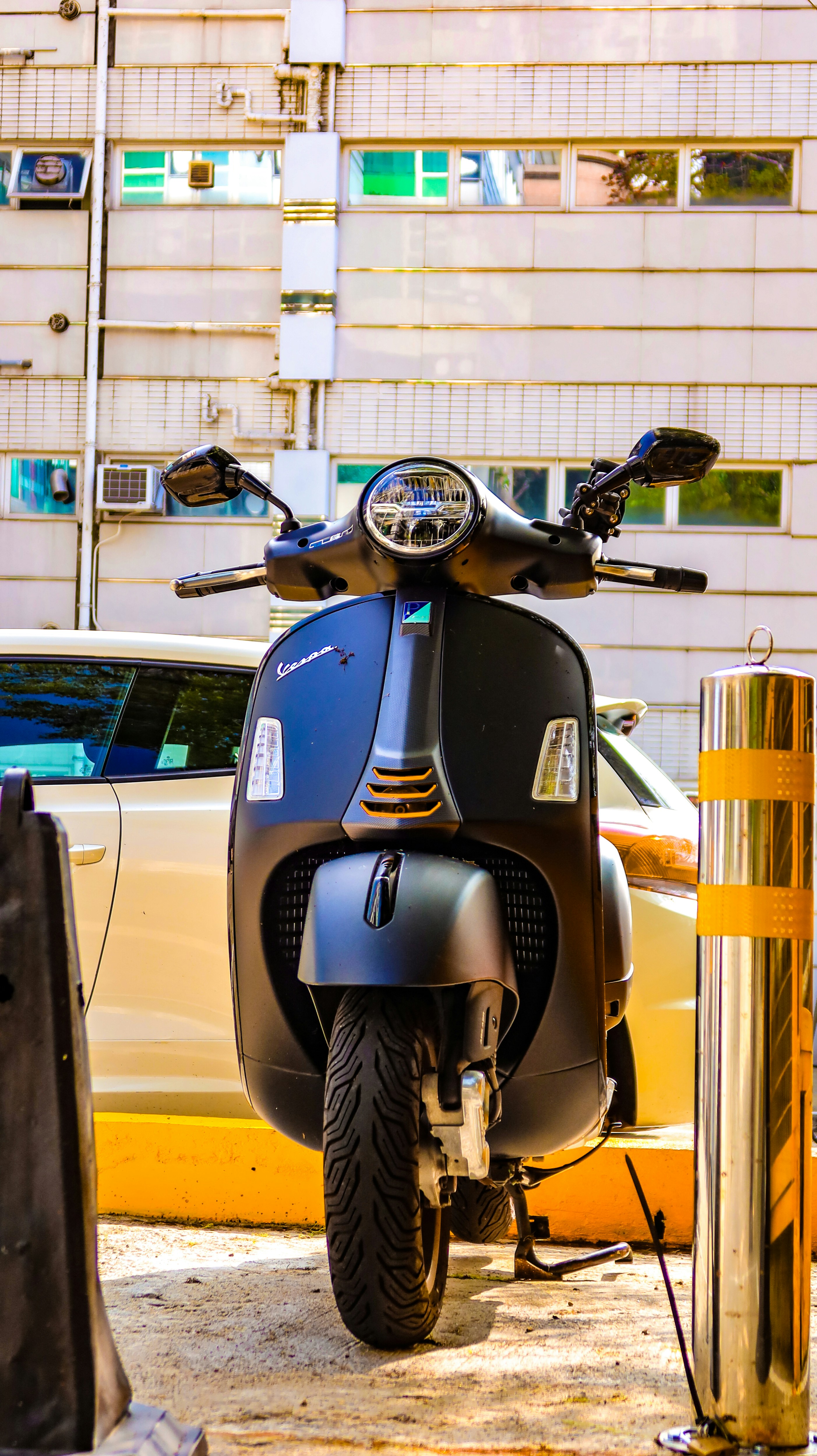 A black vespa scooter parked in front of a building.