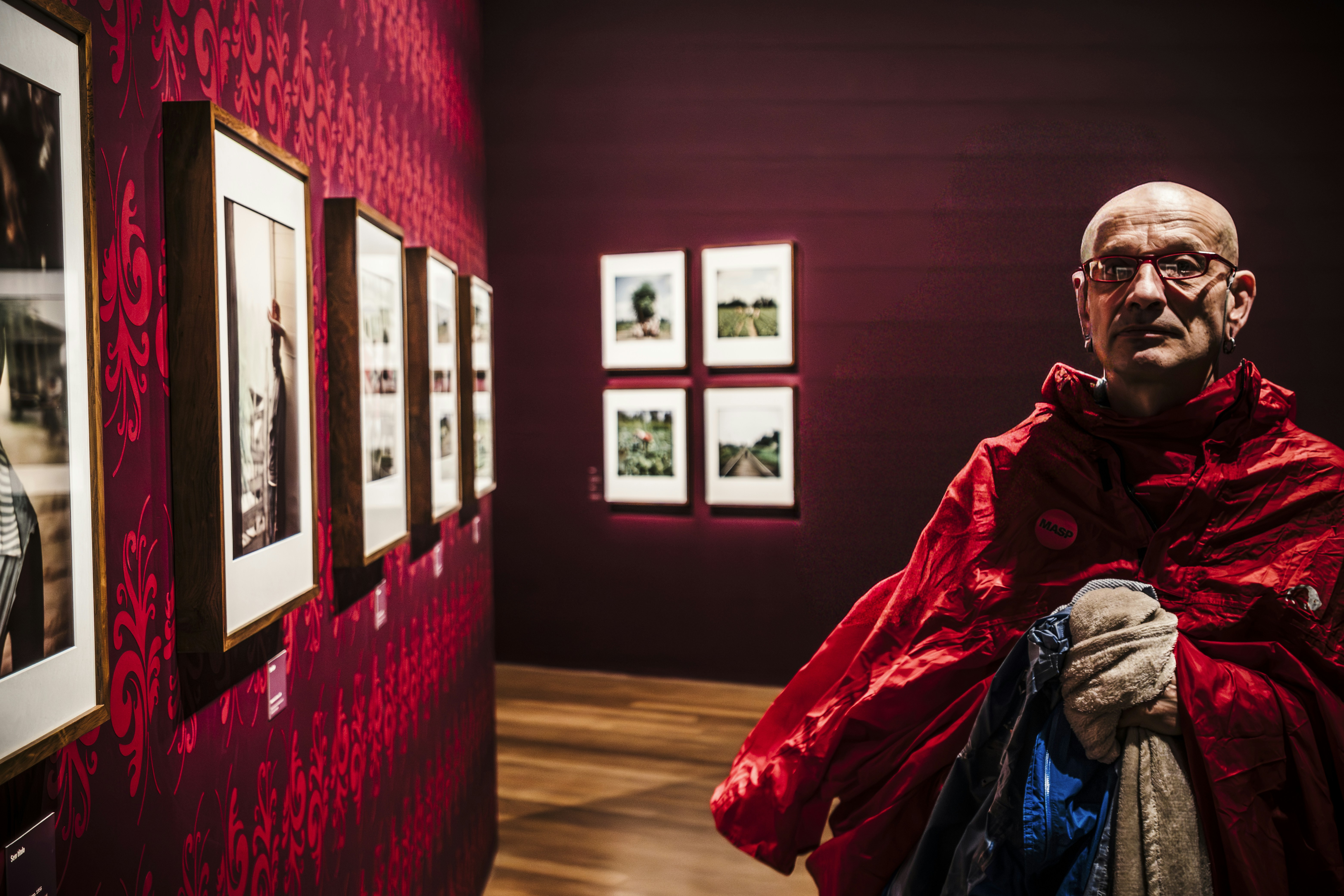 Man in red cloak stands in art gallery