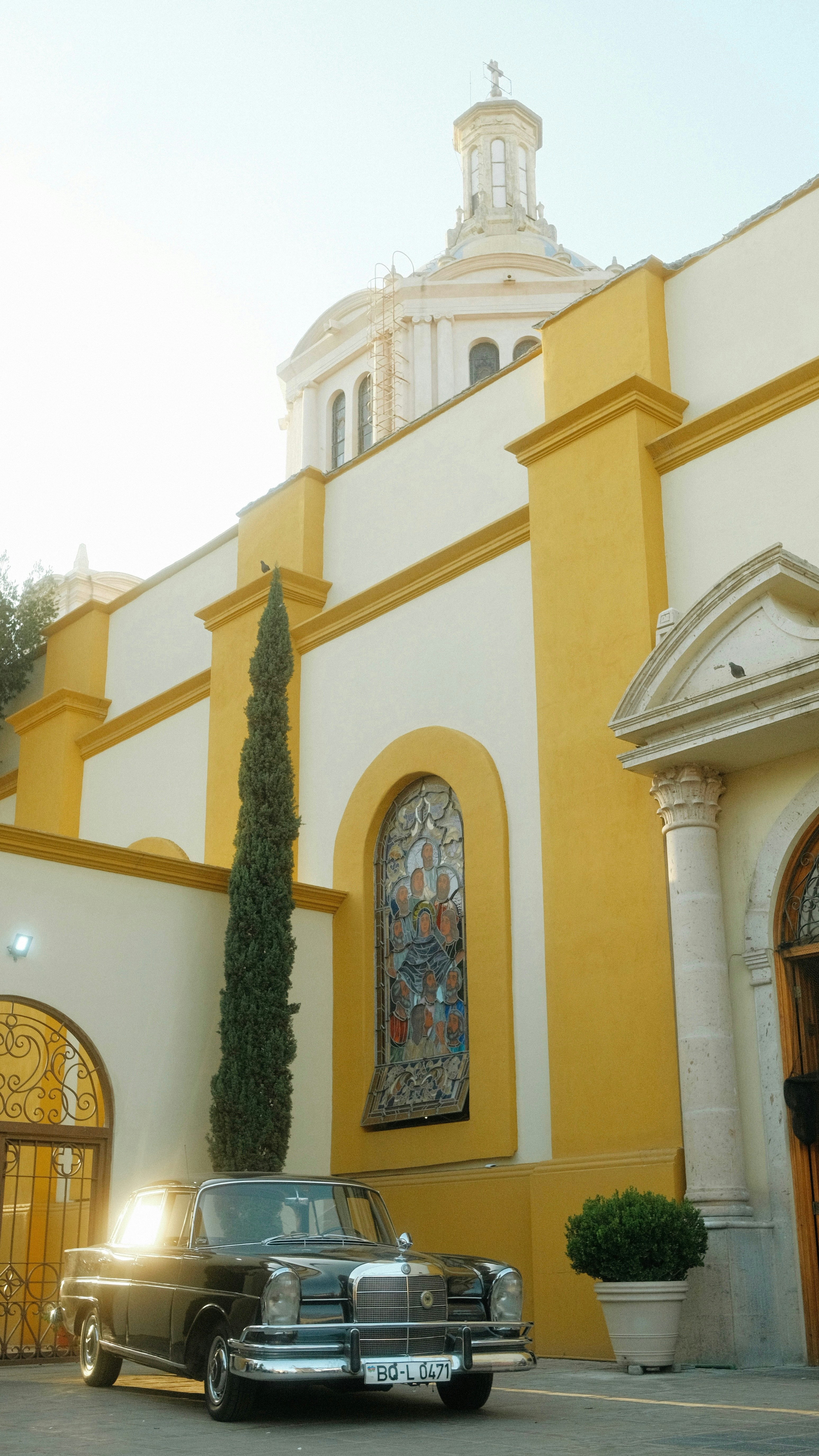 Vintage car parked outside a yellow and white building.