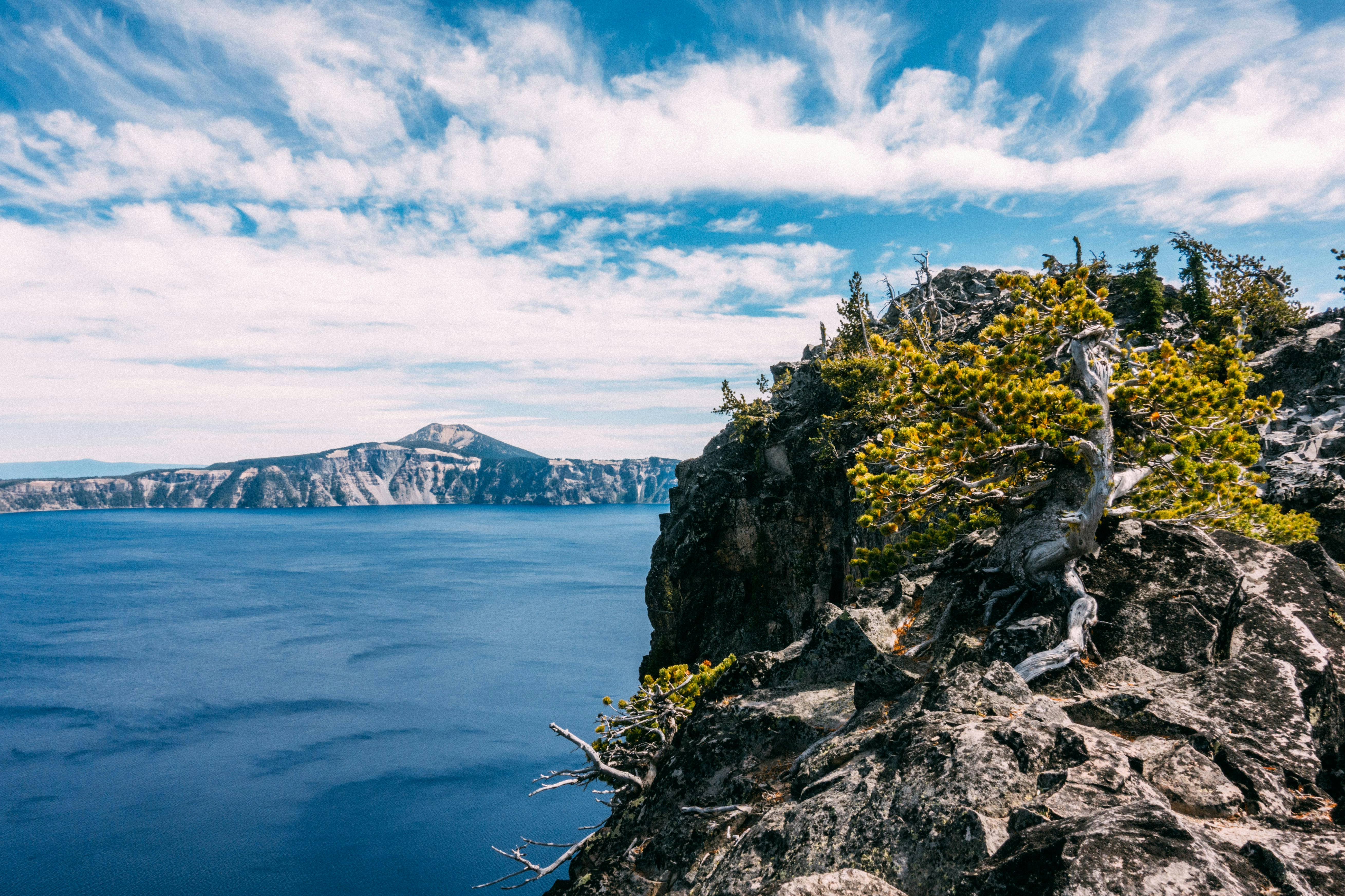 Rocky cliff overlooking a vast blue lake and distant mountains.