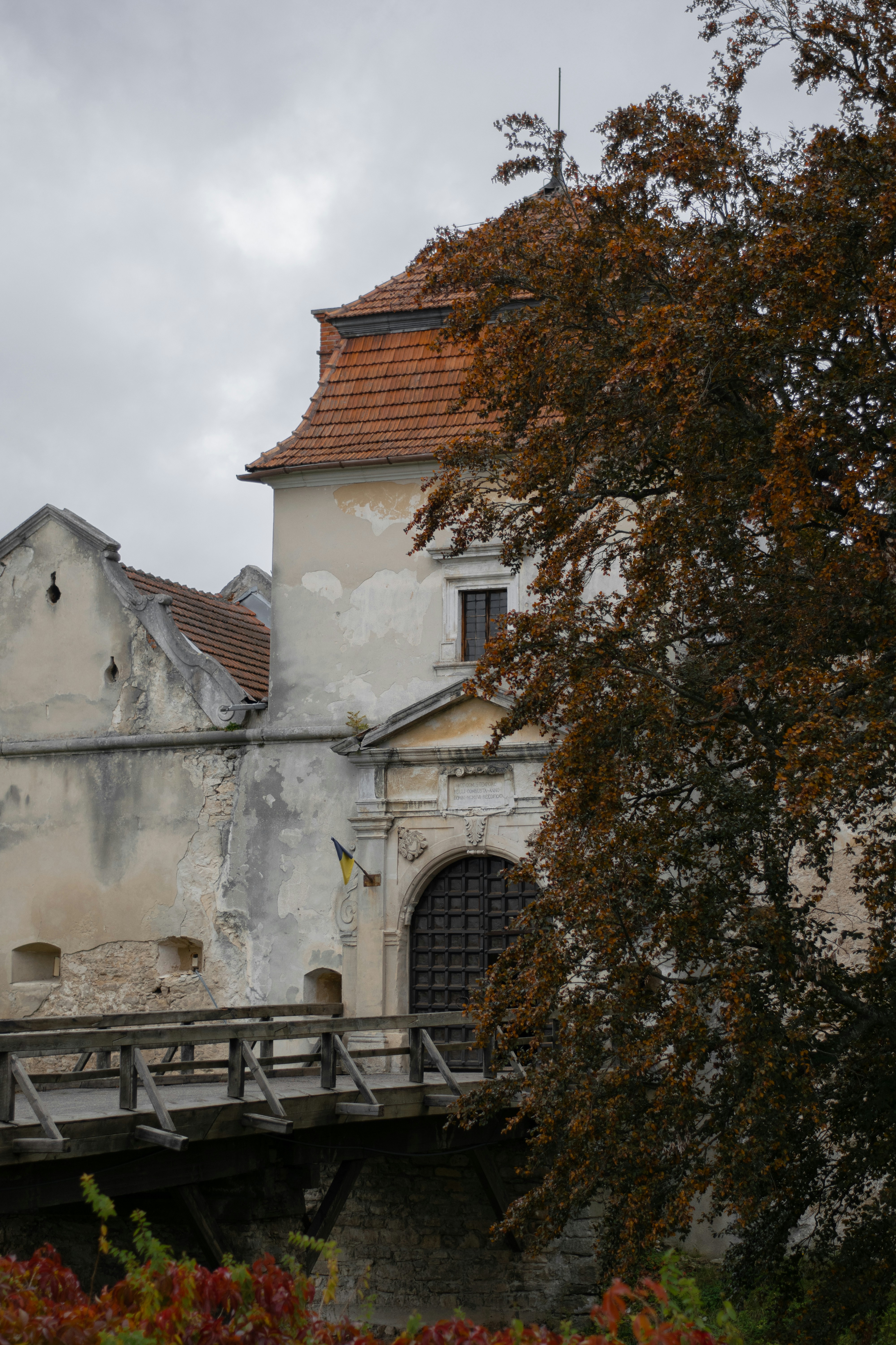 Old stone castle with wooden bridge and autumn tree