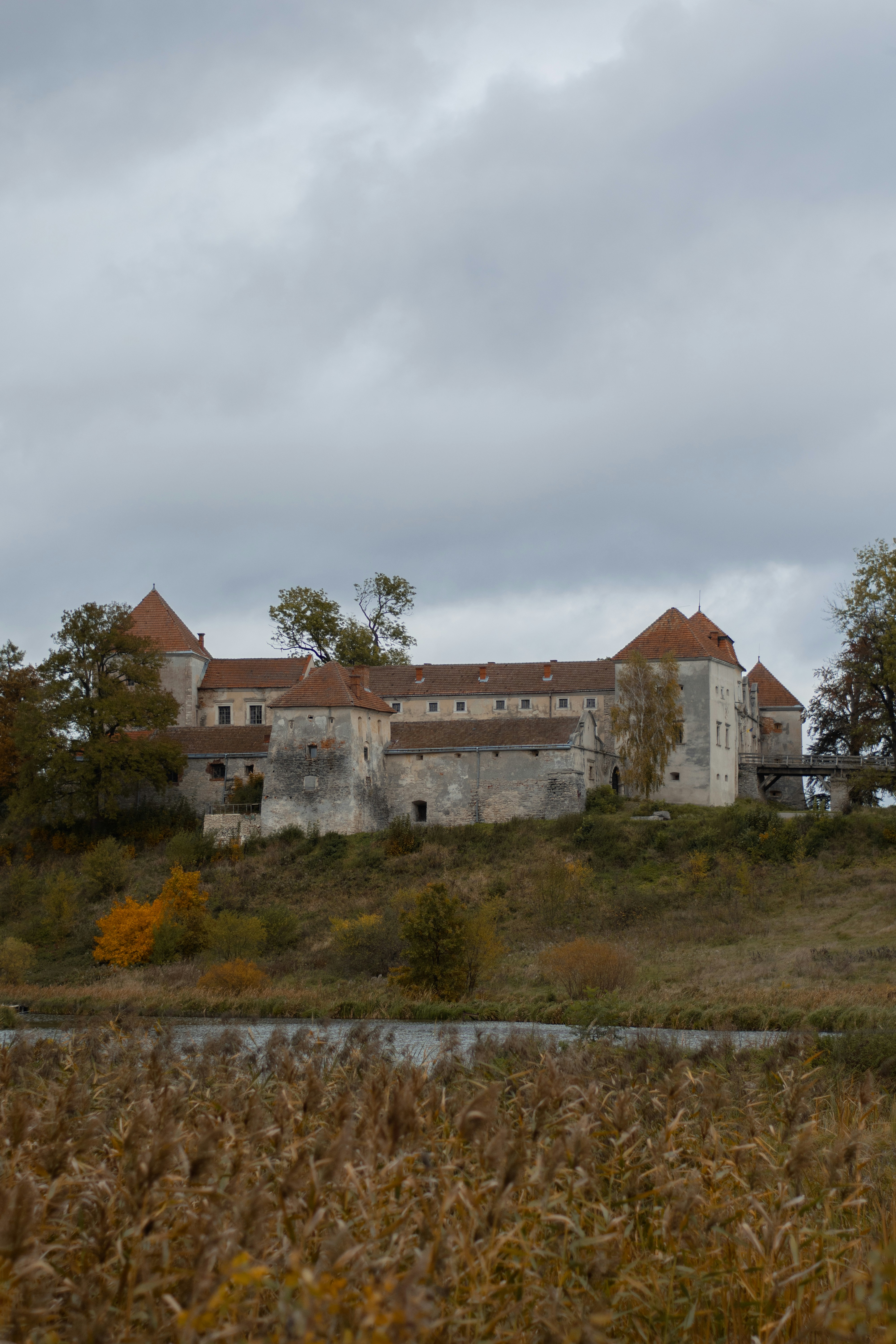 Red-Roofed Citadel Overlooking a Marsh beneath Autumn Clouds
