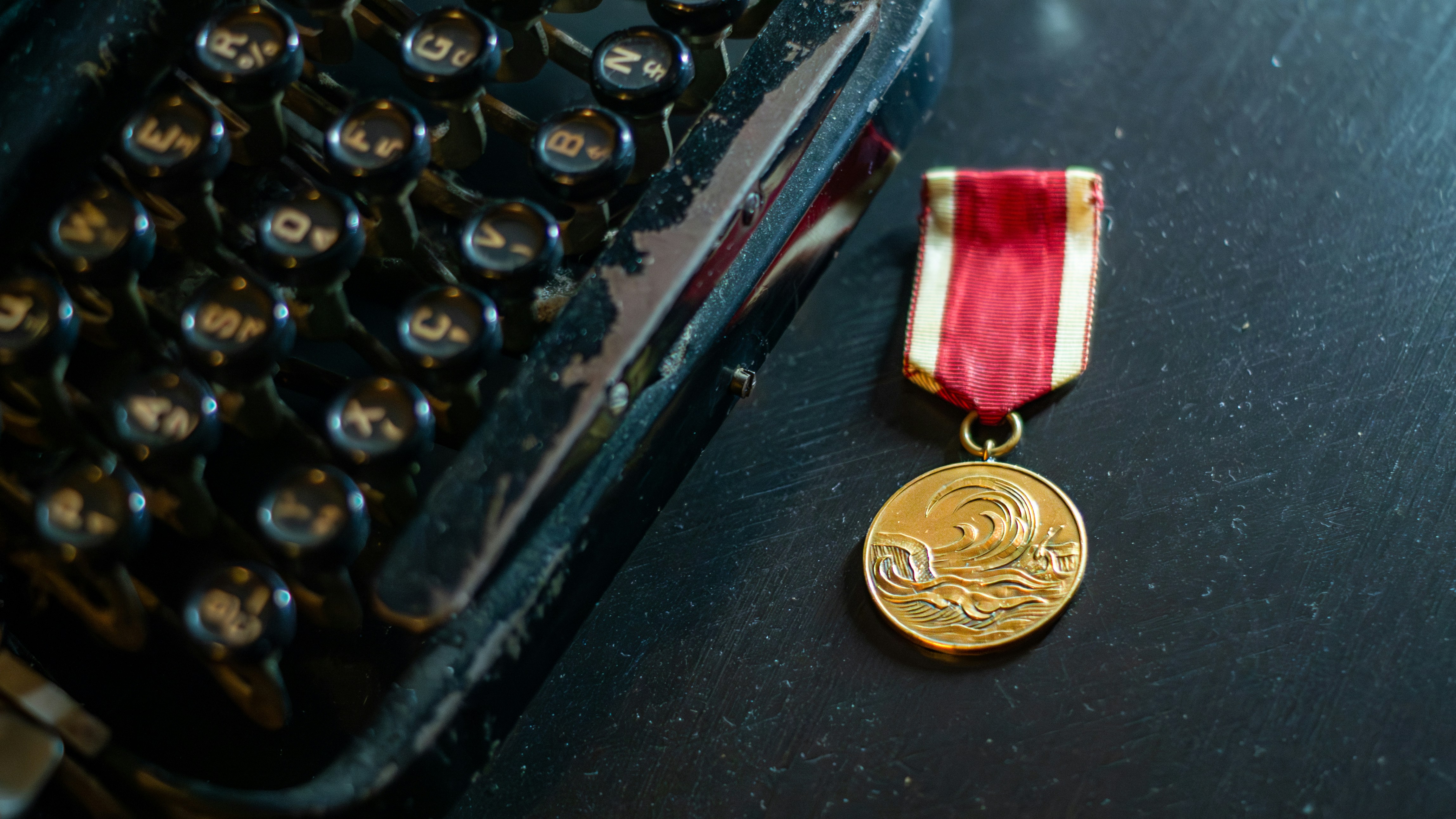 The flood medal belonging to my grandfather, who died a few months ago. He received it for his efforts in protecting the dykes during the „flood of the century“ in northern Germany in 1962. | Close-up of a medal next to a vintage typewriter.