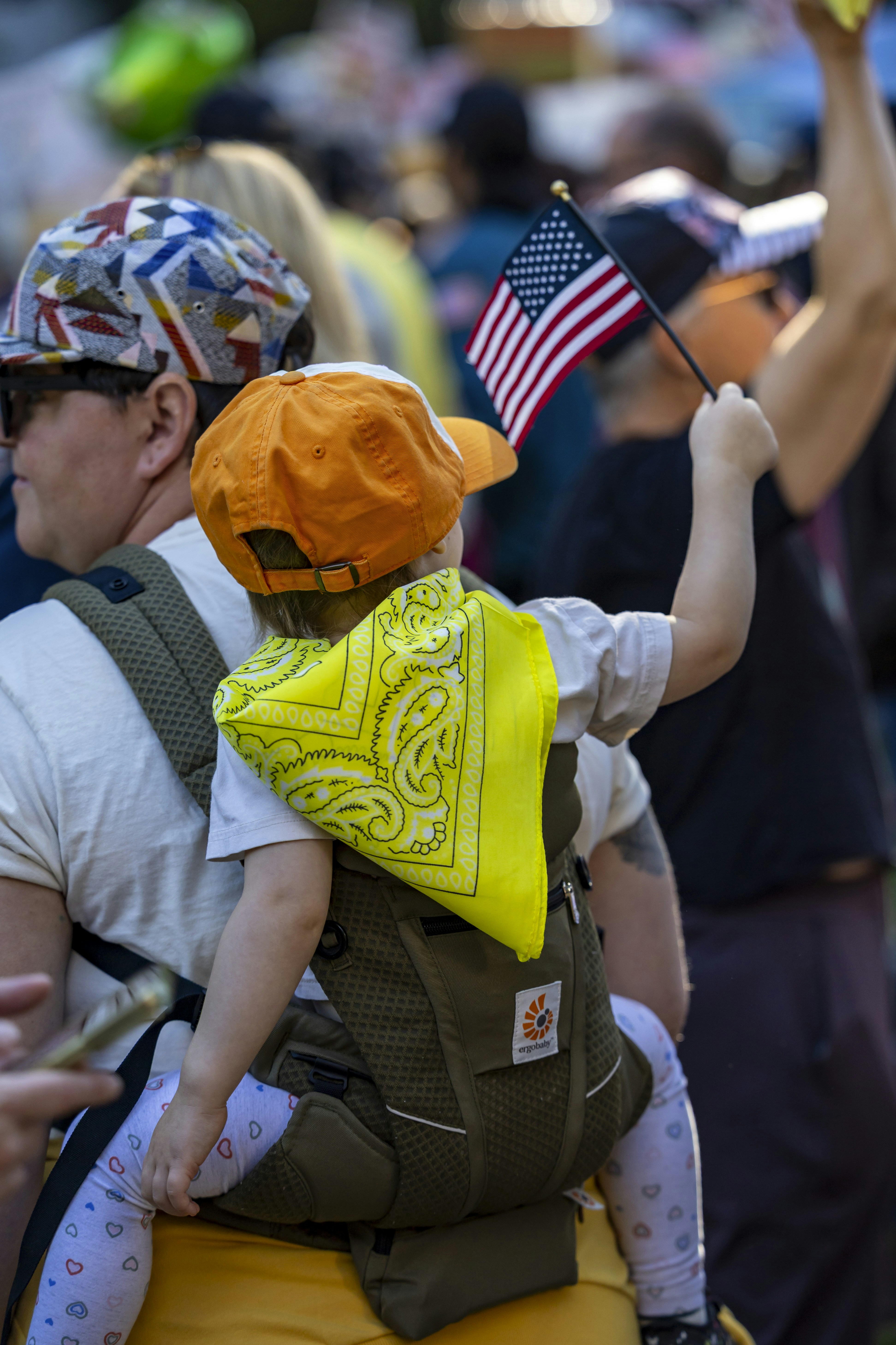 Child in carrier waves american flag at event