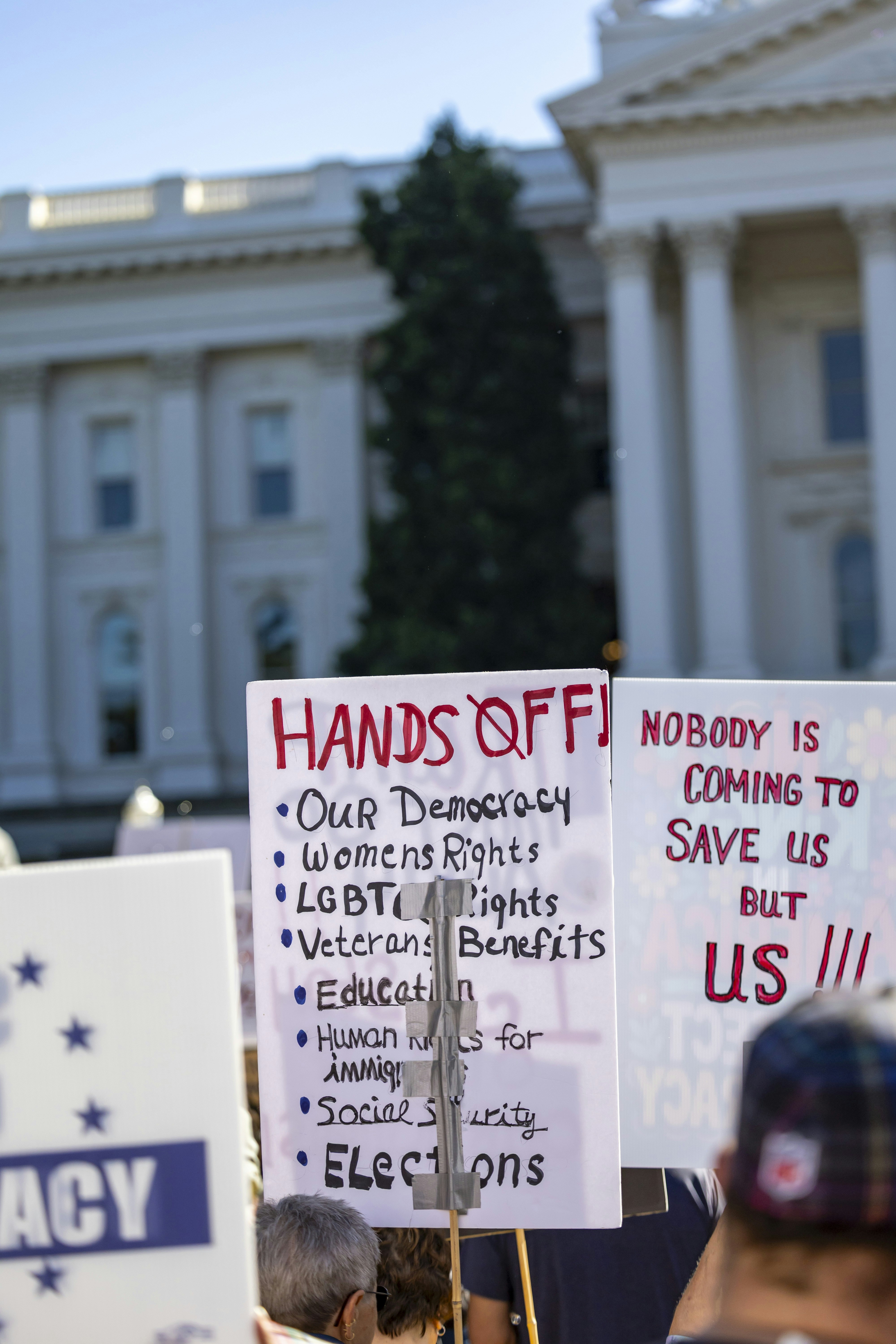 Protesters hold signs at a rally outside a government building.
