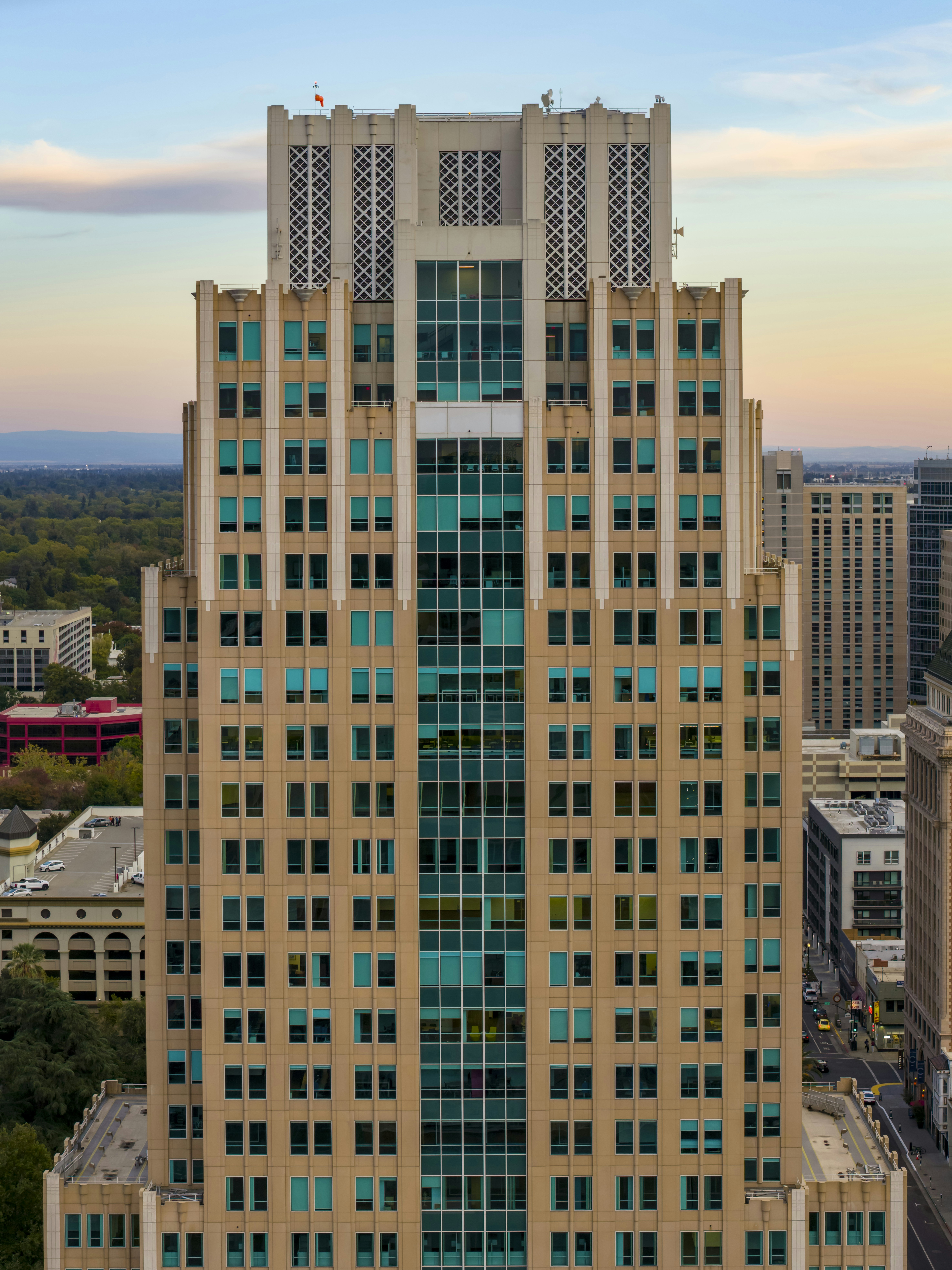Tall tan skyscraper with teal windows at sunset. photo – Free City ...