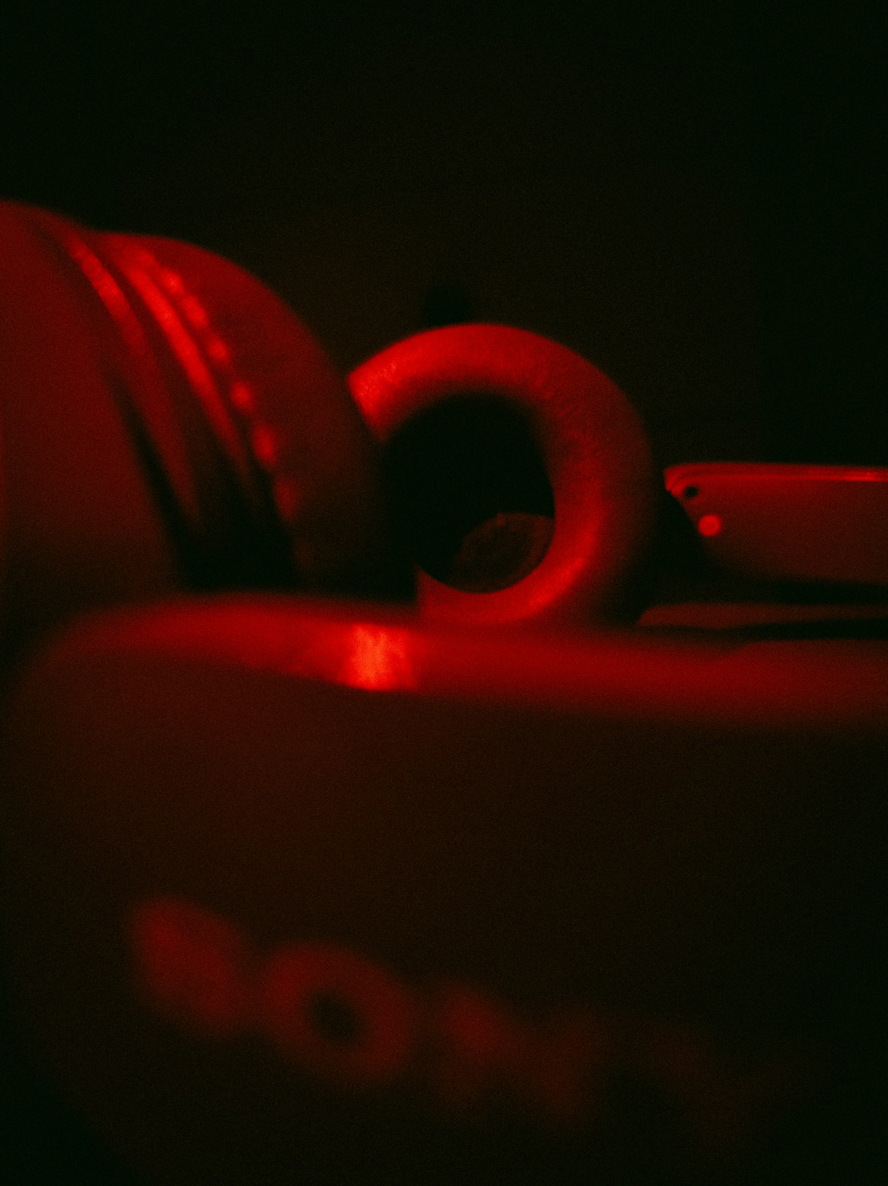 Close-up of a headphone cushion illuminated by red light, highlighting its texture and design elements. The focus is on the luxurious materials and intricate details.