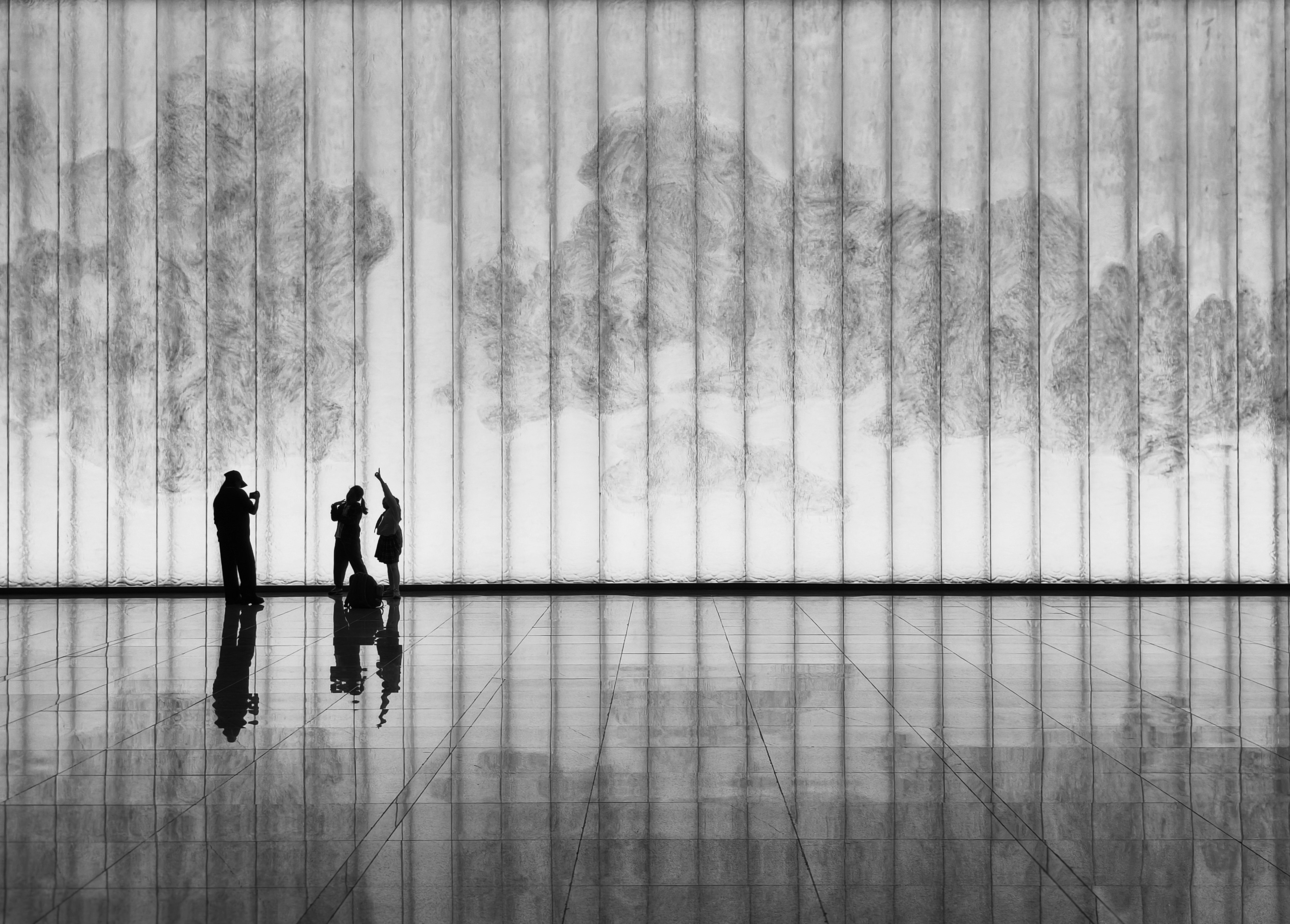Silhouettes of people reflected on a glossy floor.