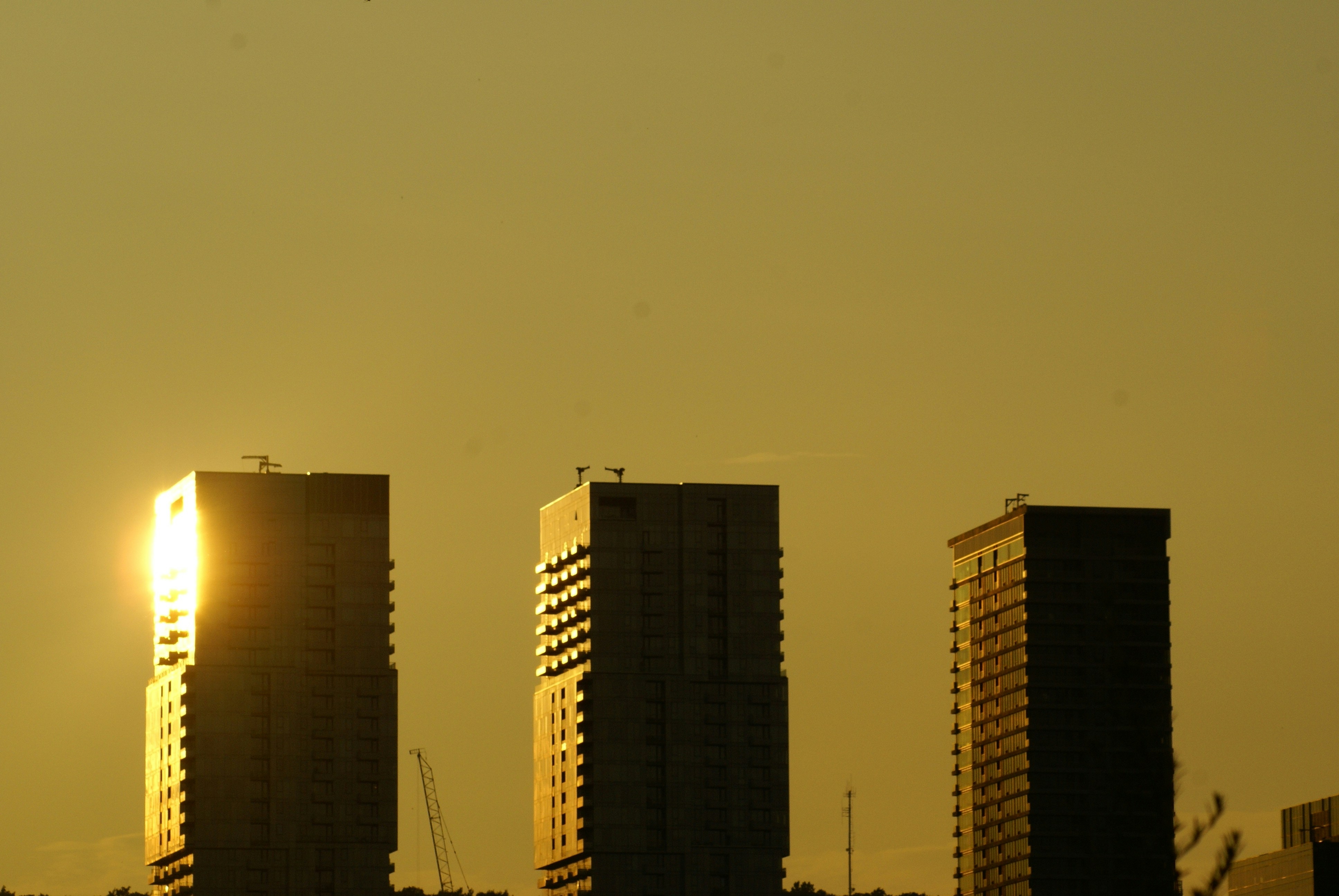 Three modern buildings silhouetted against a golden sunset.