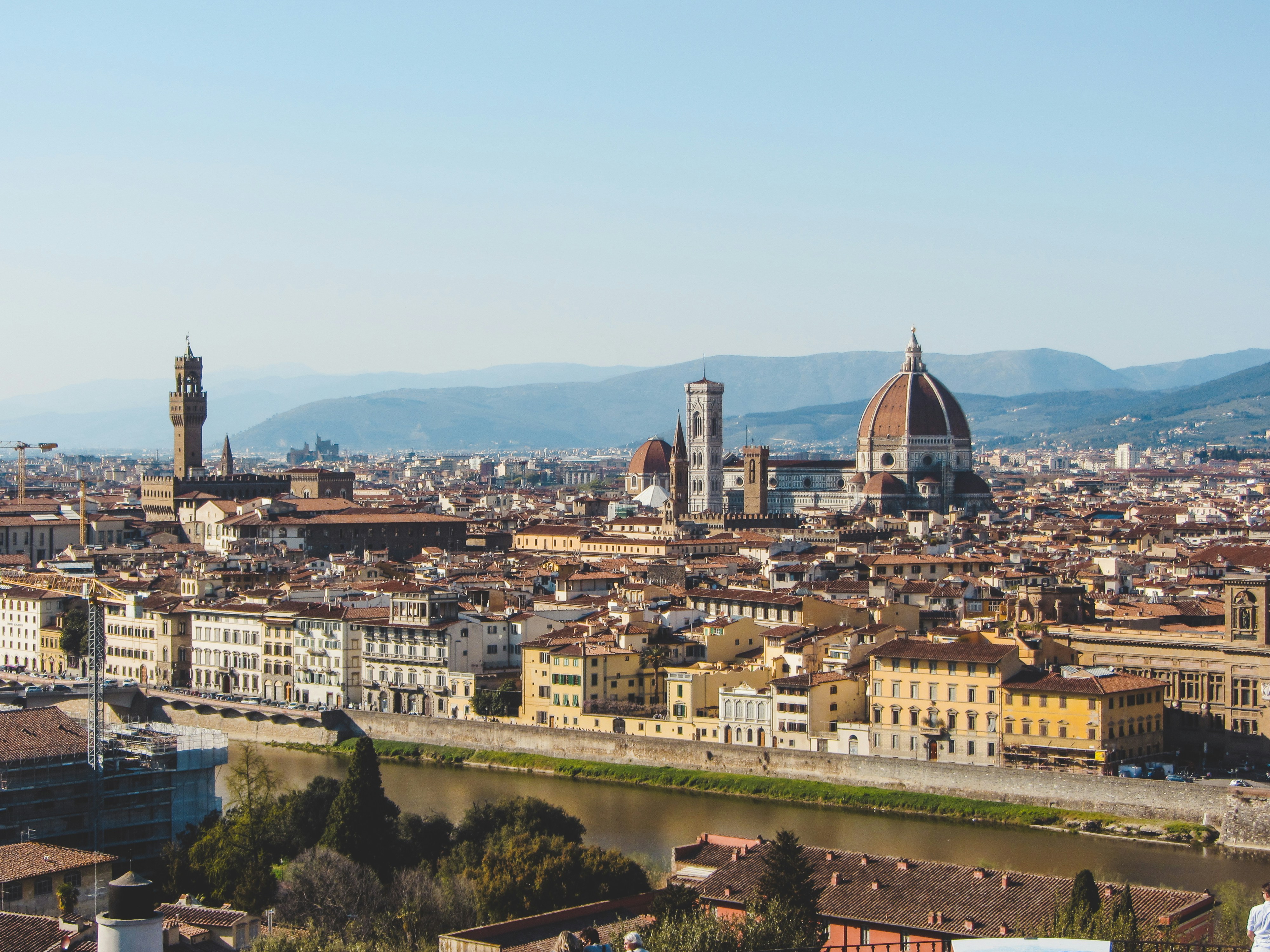 Panoramic view of Florence showcasing iconic landmarks including the Duomo and Palazzo Vecchio, with the Arno River flowing below.