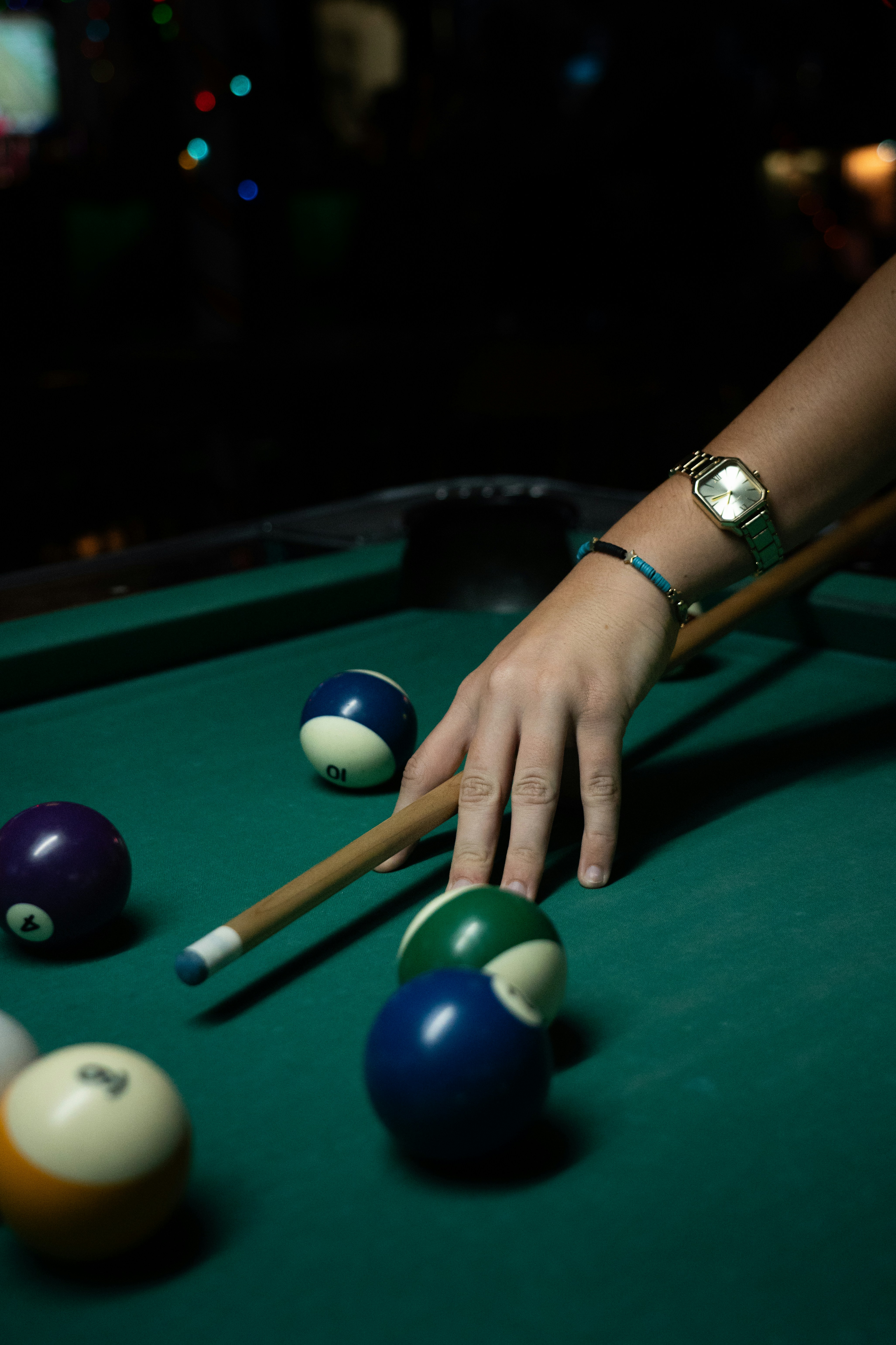 A focused hand poised over a vibrant pool table, preparing to break the arrangement of colorful billiard balls.