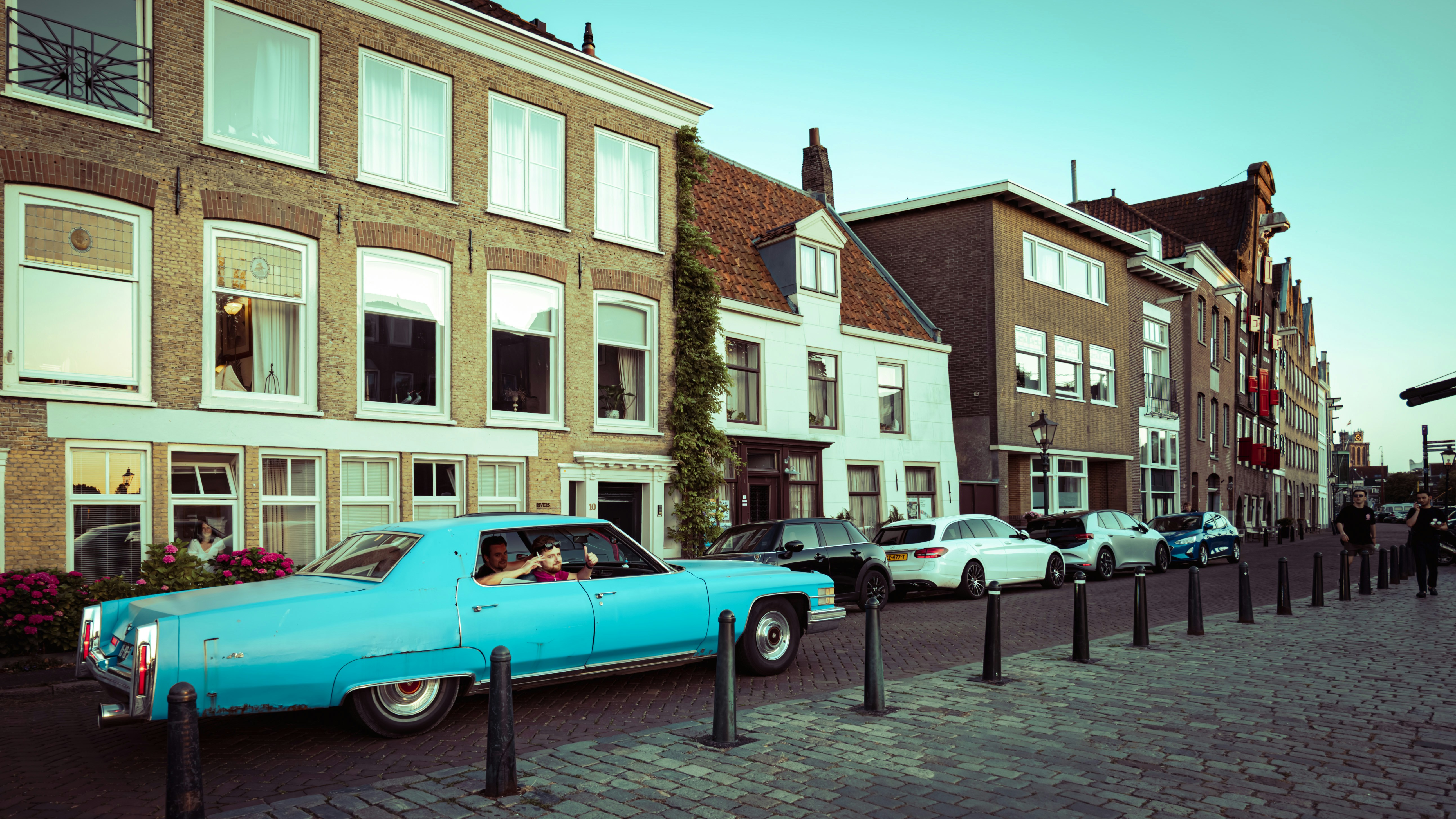 Cadillac De Ville in Dordrecht Netherlands. | Blue classic car driving down a european street.